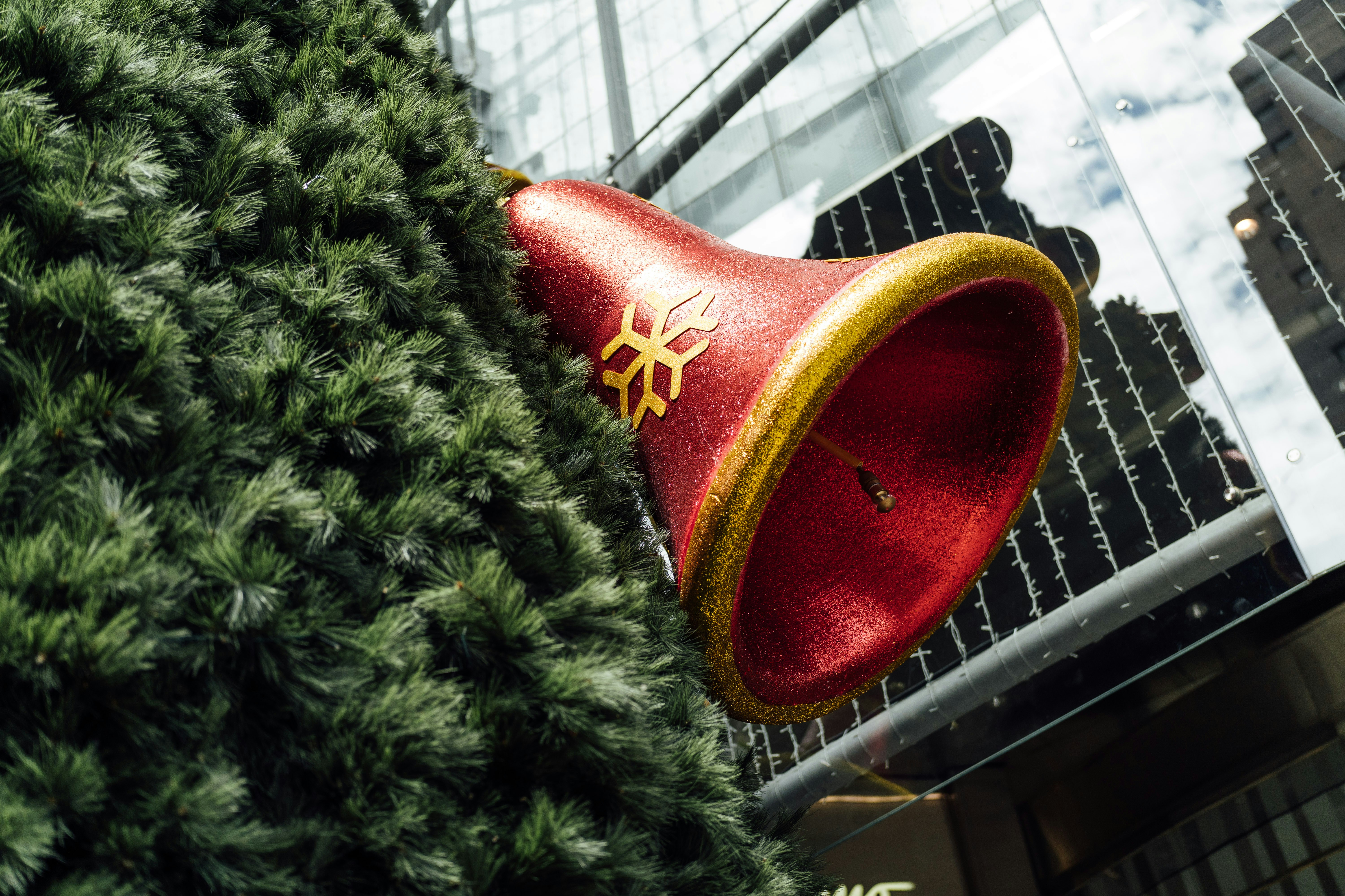 Crimson Bell in a Glassy Cityscape Amid Evergreen Needles