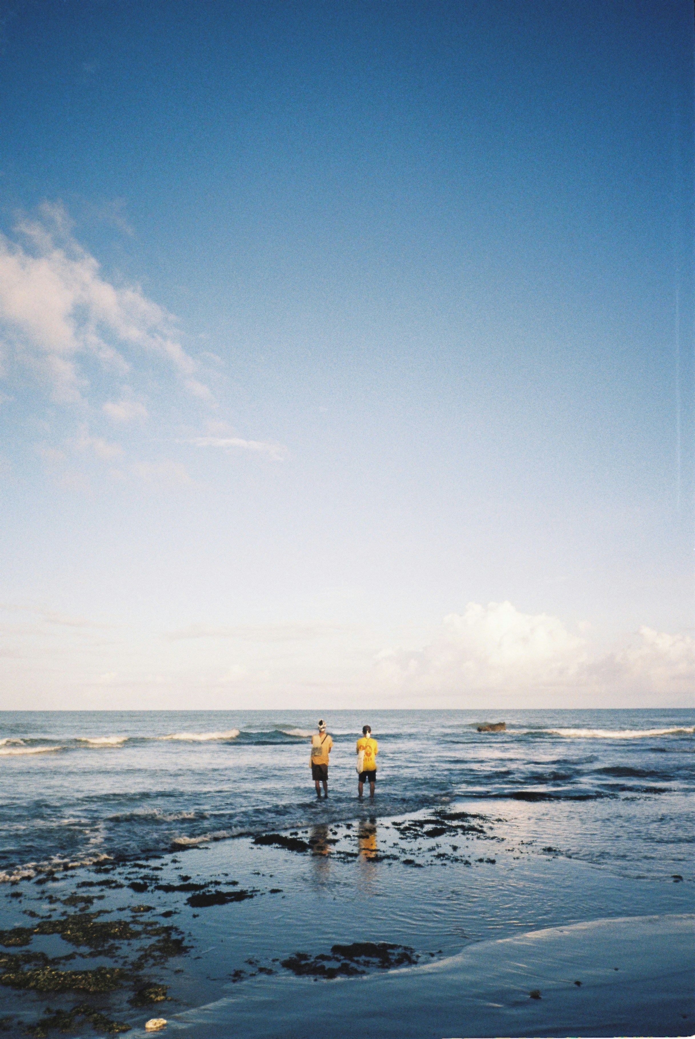Two people standing on a beach next to the ocean photo – Free Indonesia ...