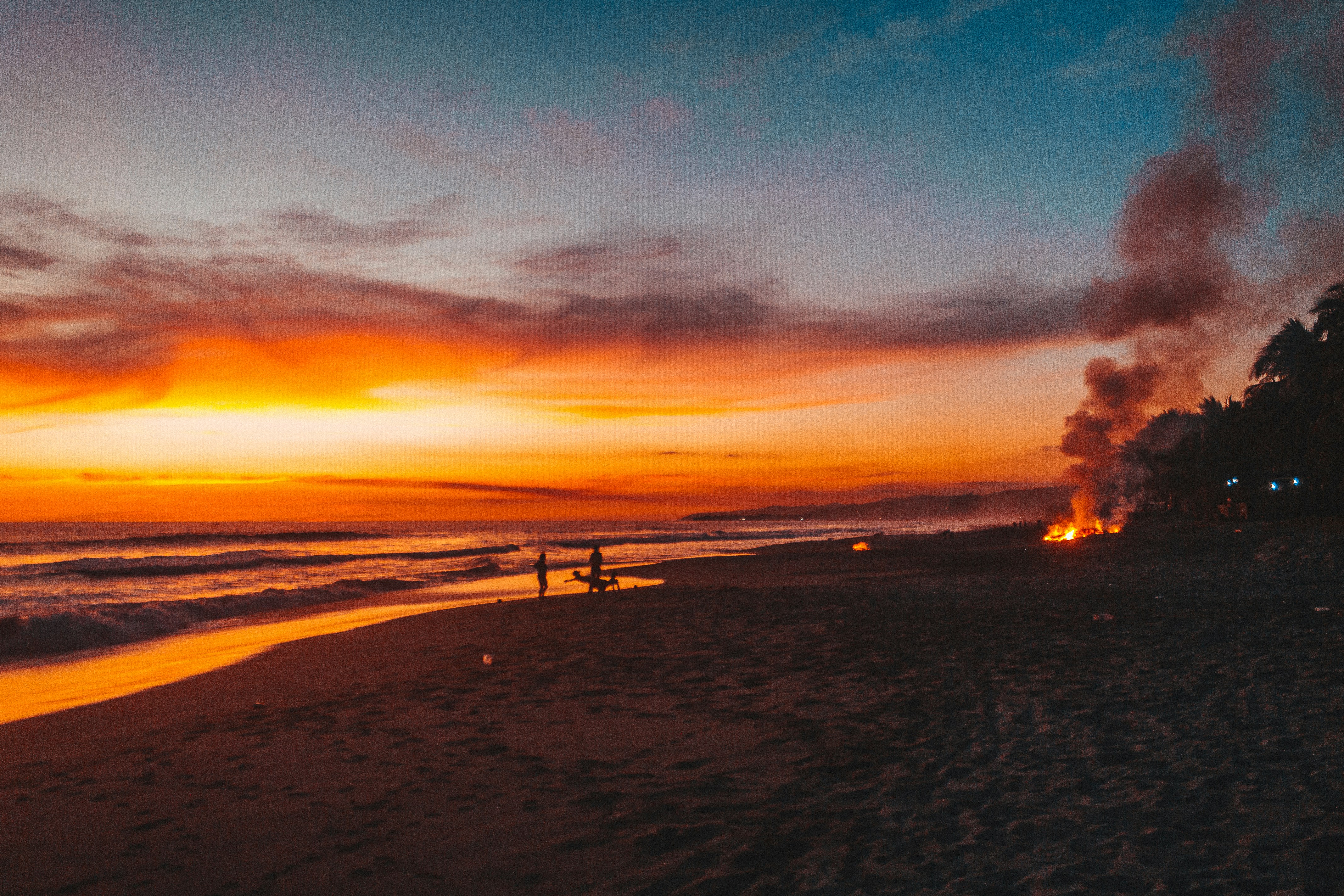 Sunset on the Beach: Flames and Silhouettes Along the Shore