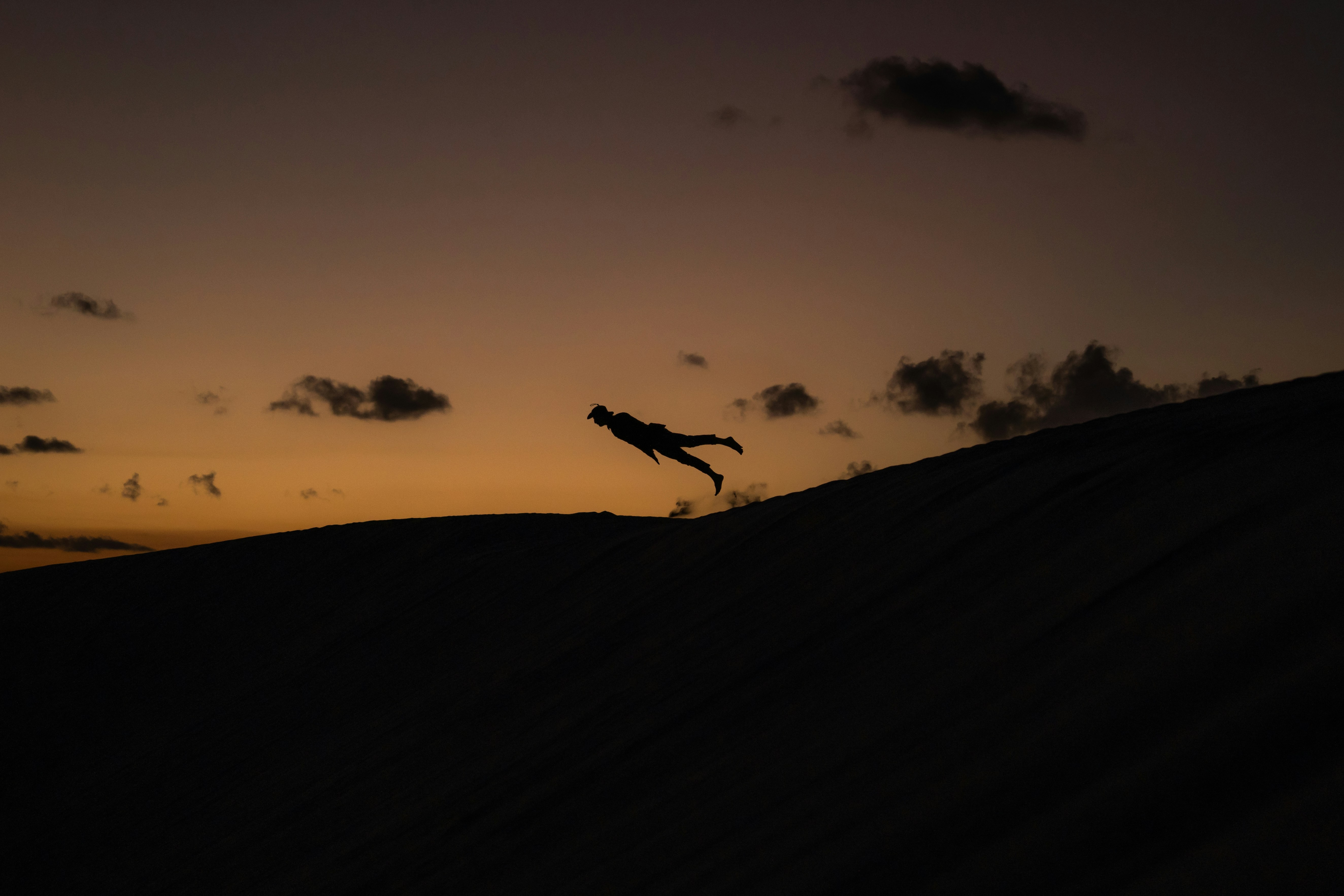 Dusk Leap: A Lone Silhouette Arcs Over a Dune Crest