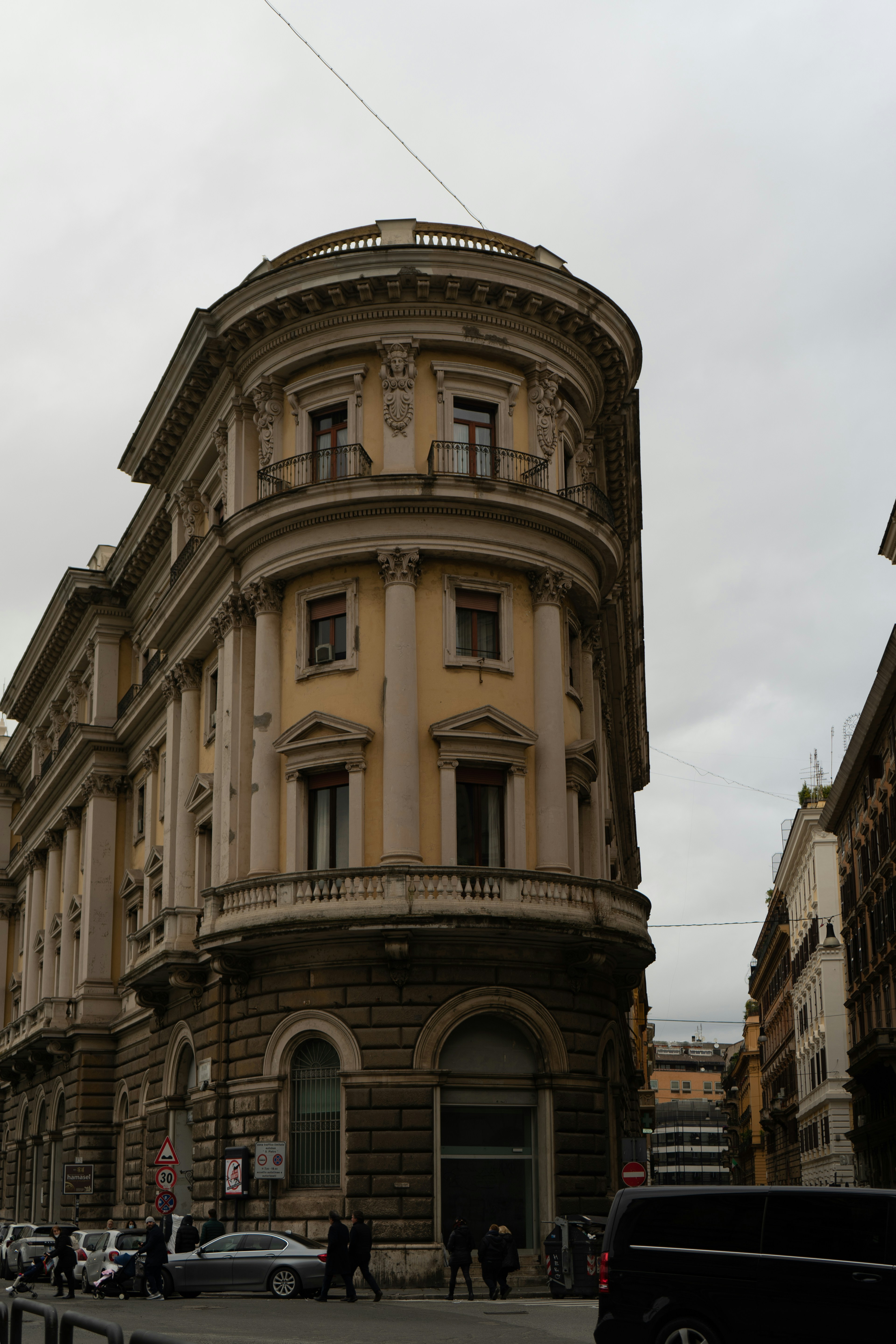 Historic building with intricate detailing and a rounded façade, set against a cloudy sky. The structure showcases classic architectural elements.
