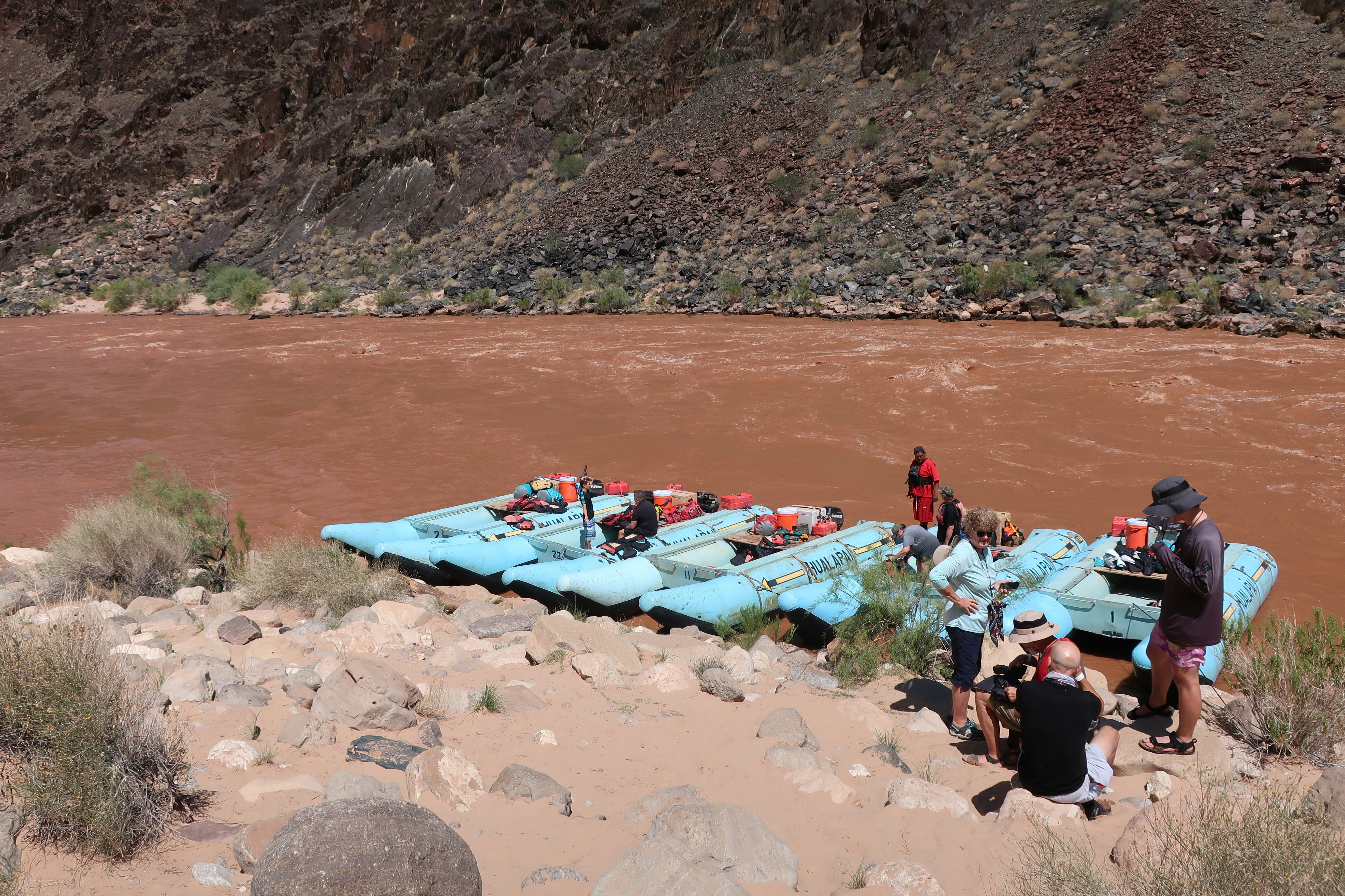 A group of people standing around a raft on the side of a river photo ...
