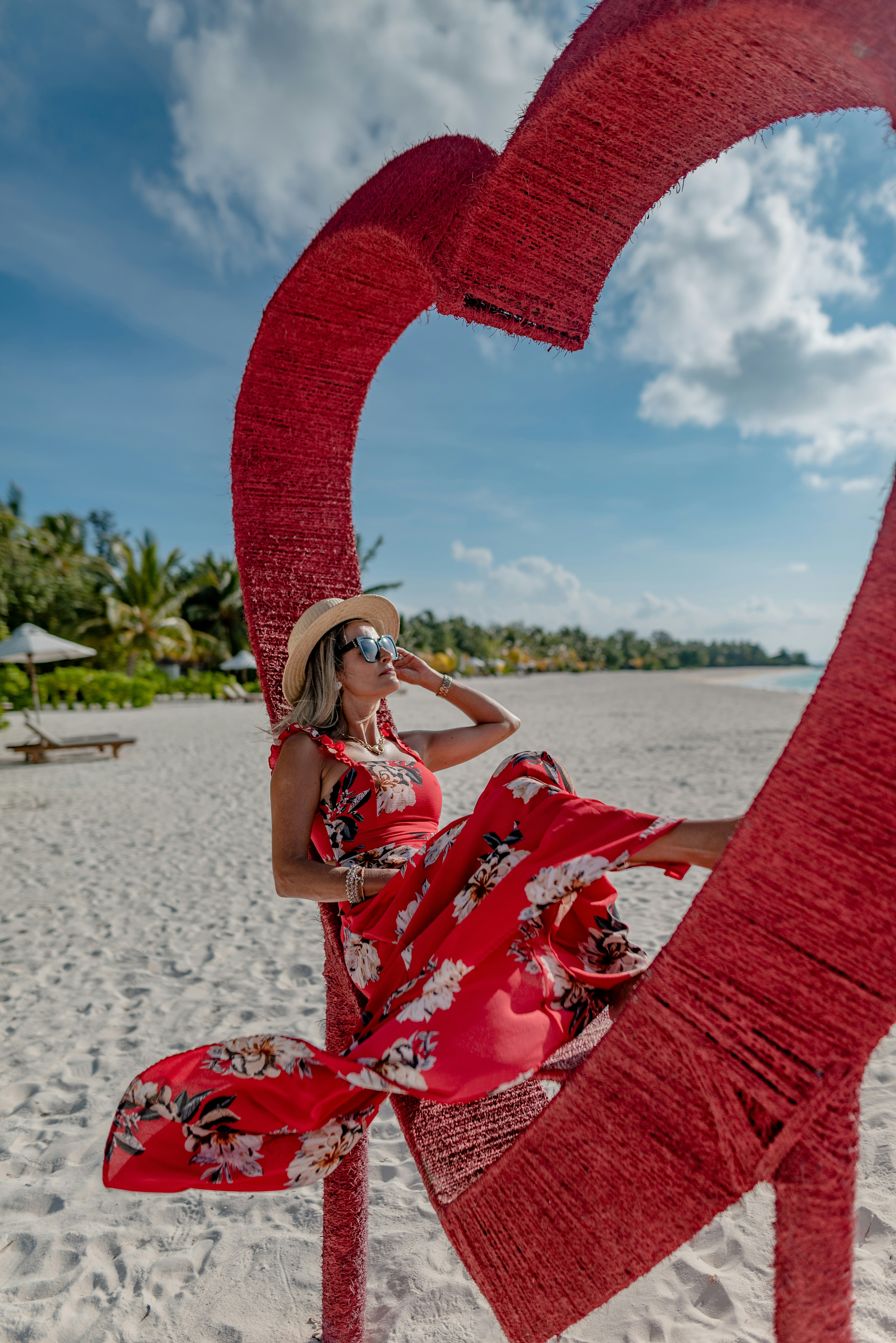 Red curve, bright dress: a sunlit beach moment framed by sculpture
