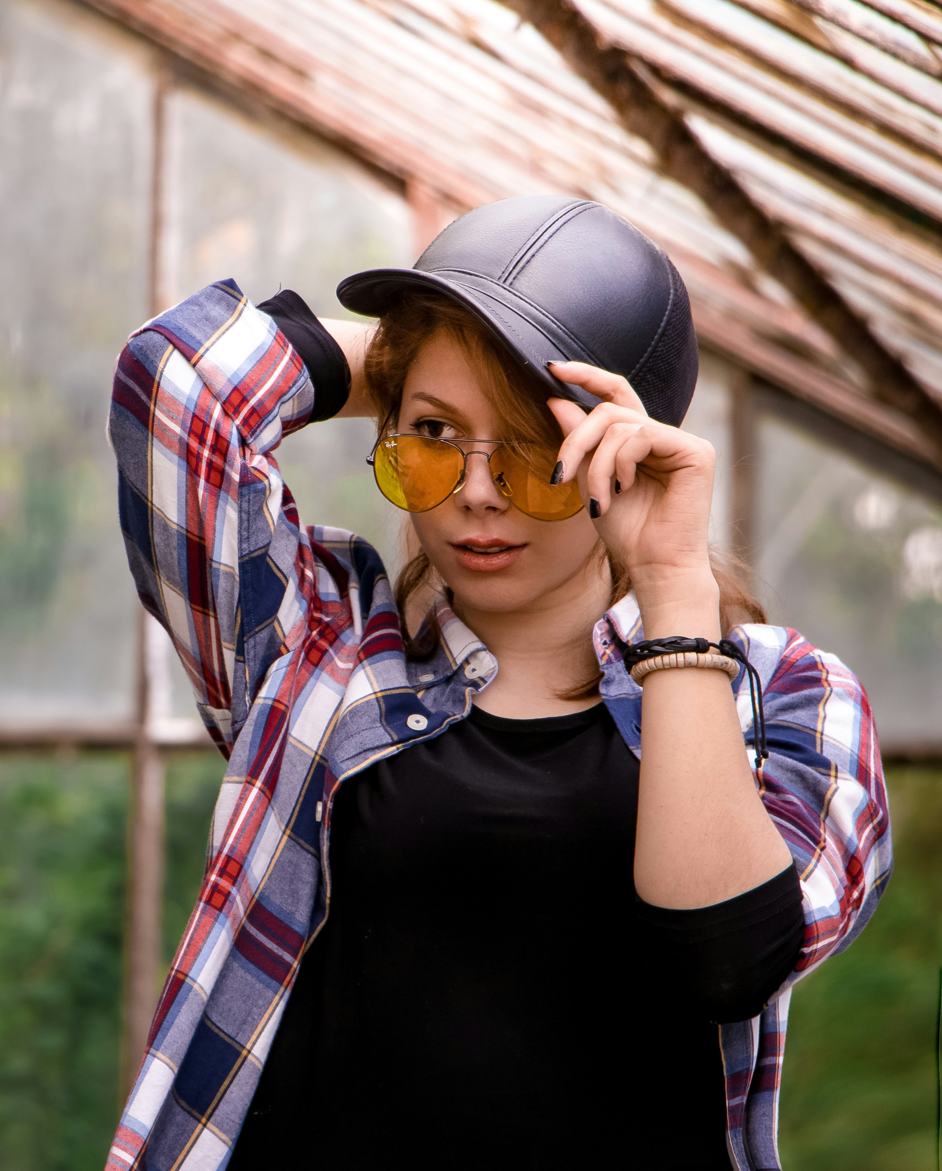 Plaid Portrait: Golden Glasses and a Cap in a Sunlit Greenhouse Backdrop