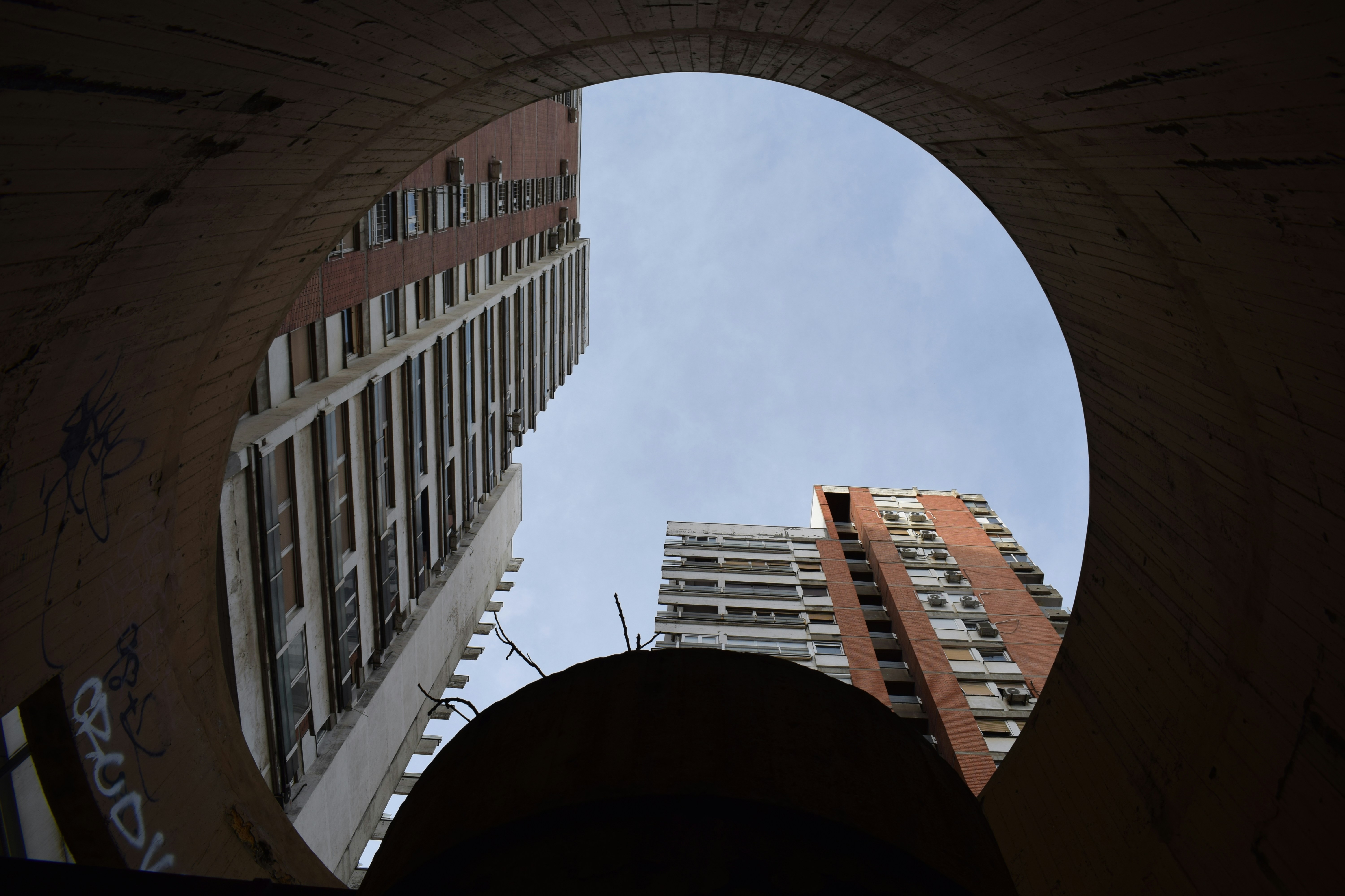 Looking up at tall buildings through a hole in a wall photo – Free Blue ...