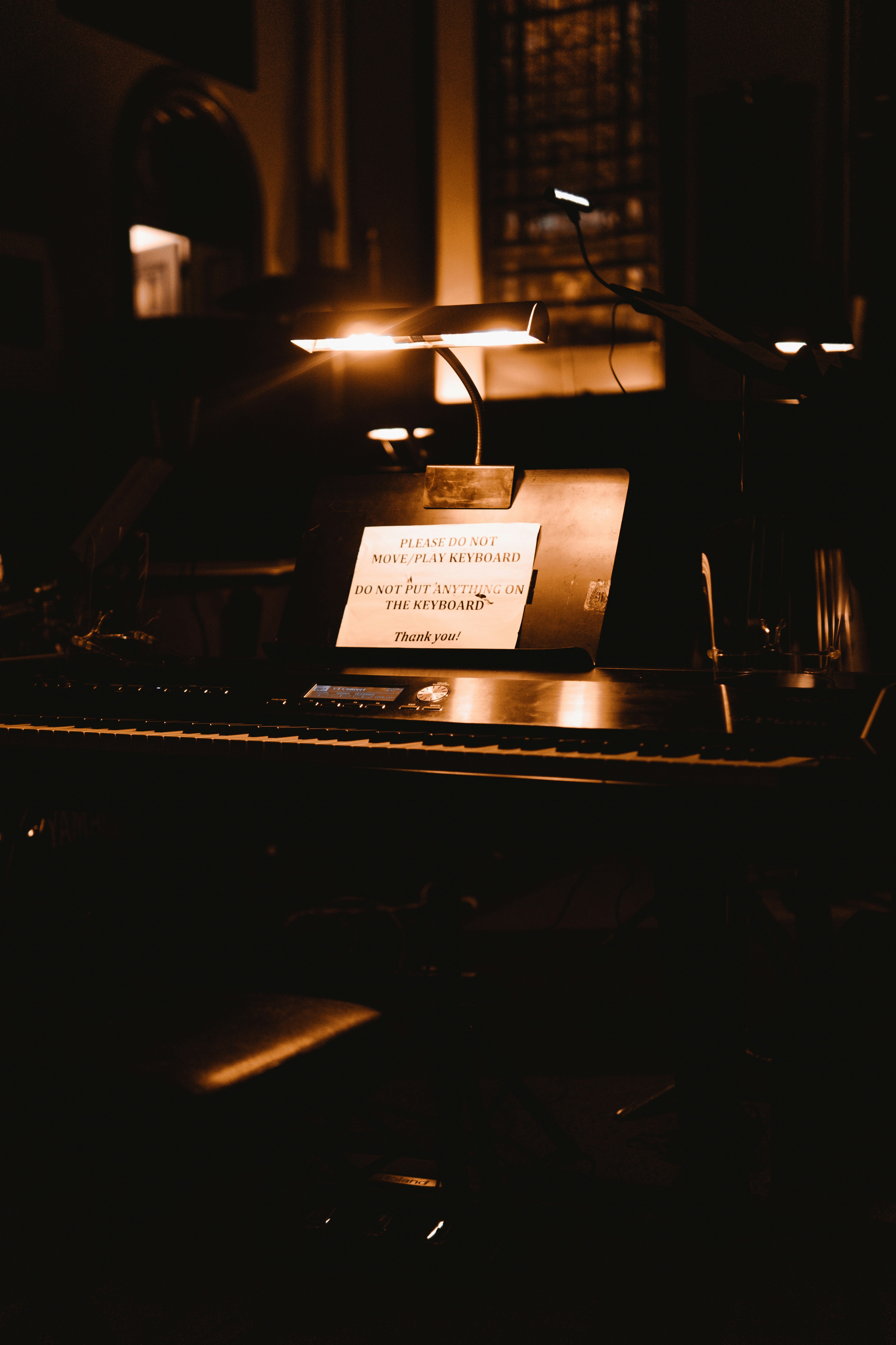 A piano with a note attached to it in a dark room photo – Free Interior ...