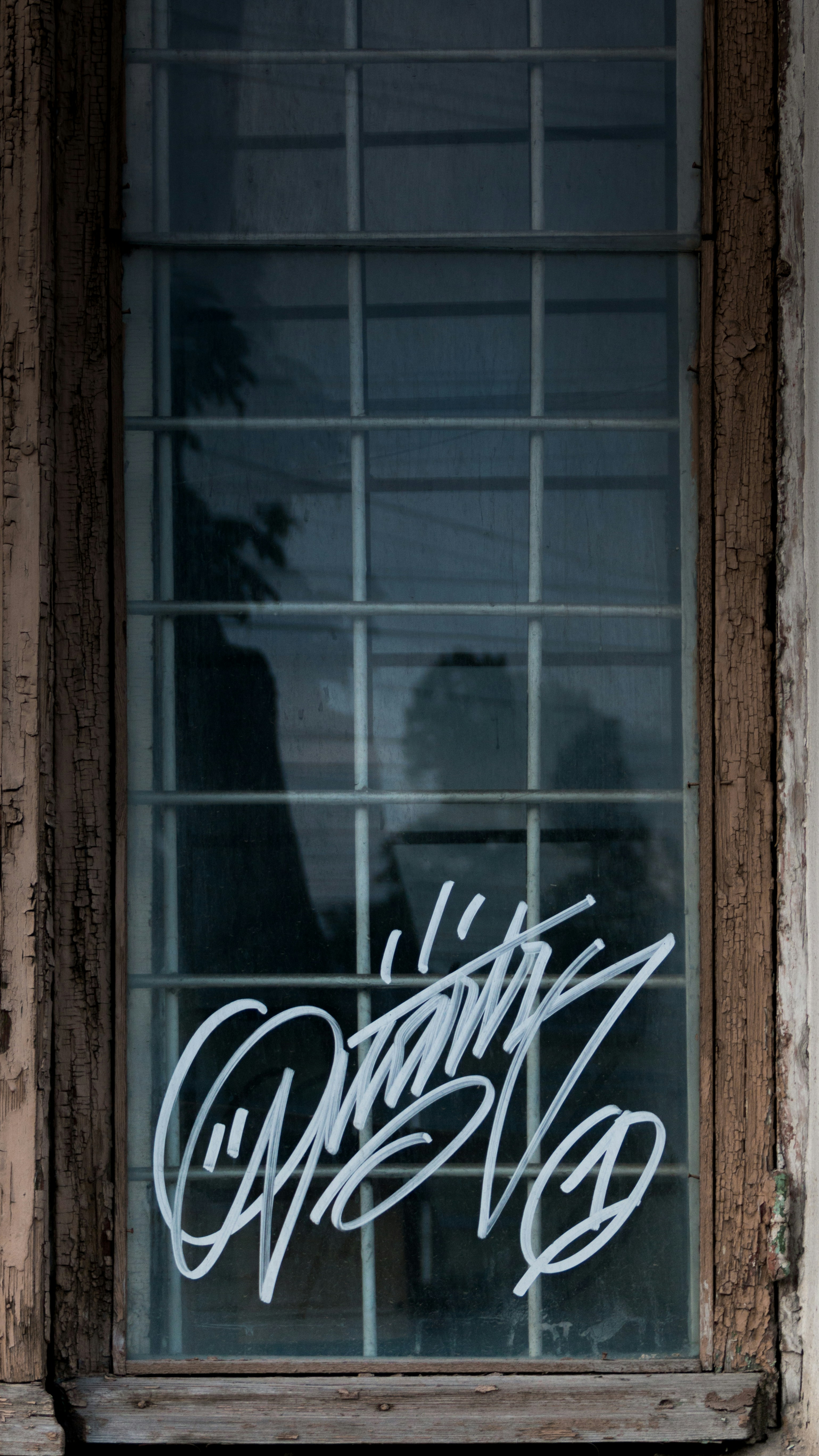 Ink on Glass: Graffiti Casting Shadows Across a Weathered Window Grid