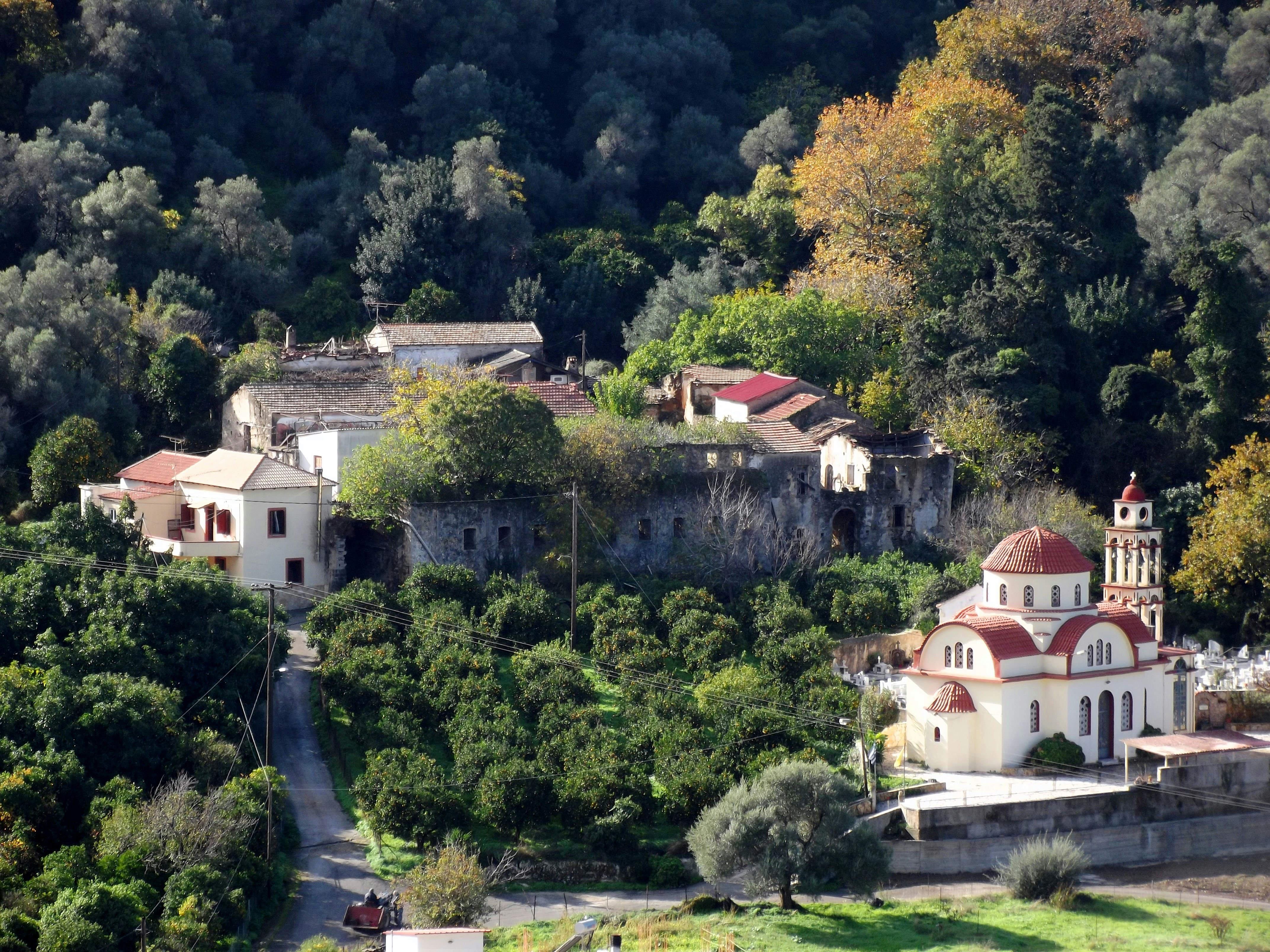 Charming hillside village featuring traditional architecture and a quaint church surrounded by vibrant orchards.
