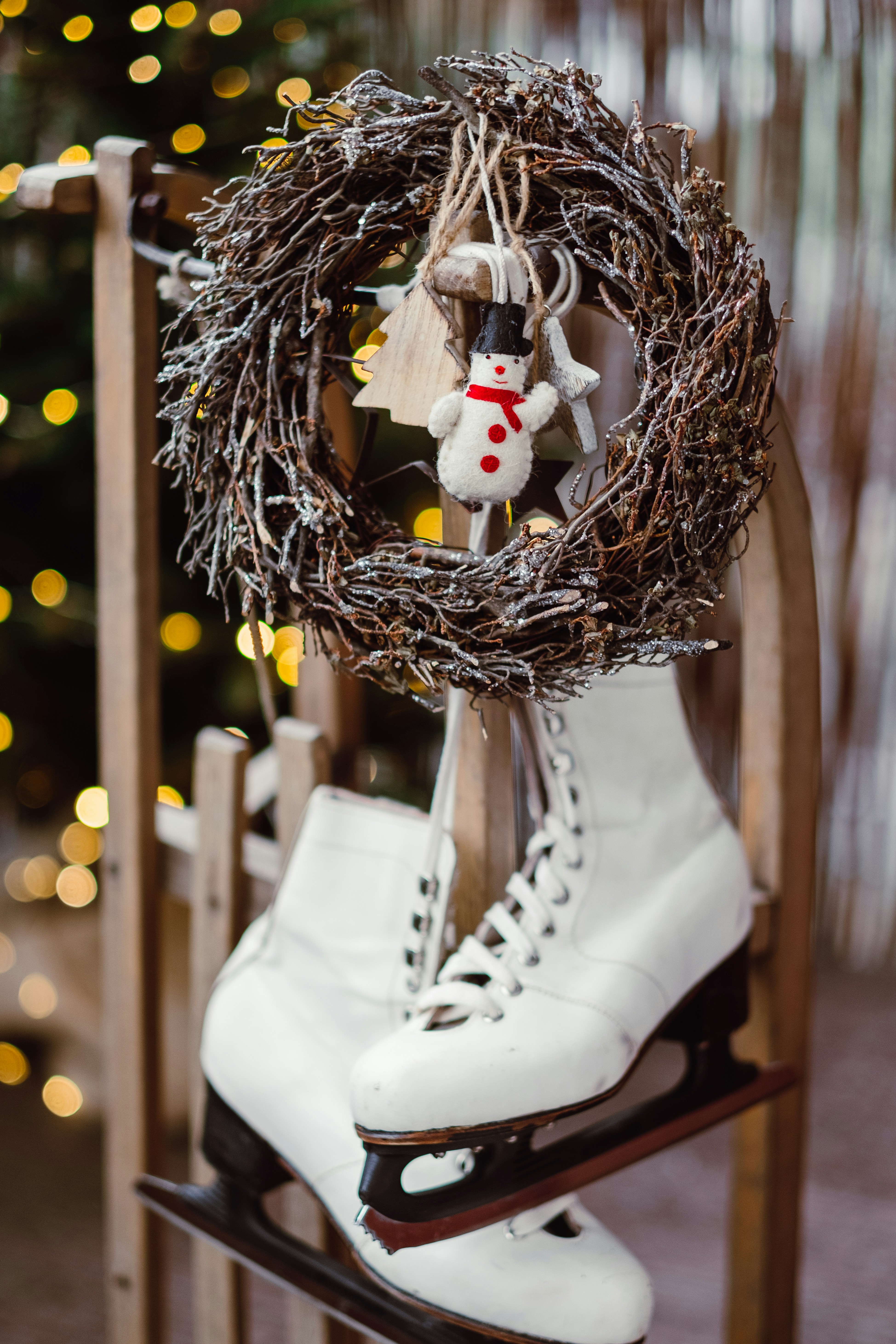 A charming holiday wreath adorned with a snowman hangs above a pair of classic white ice skates, evoking a cozy winter atmosphere.