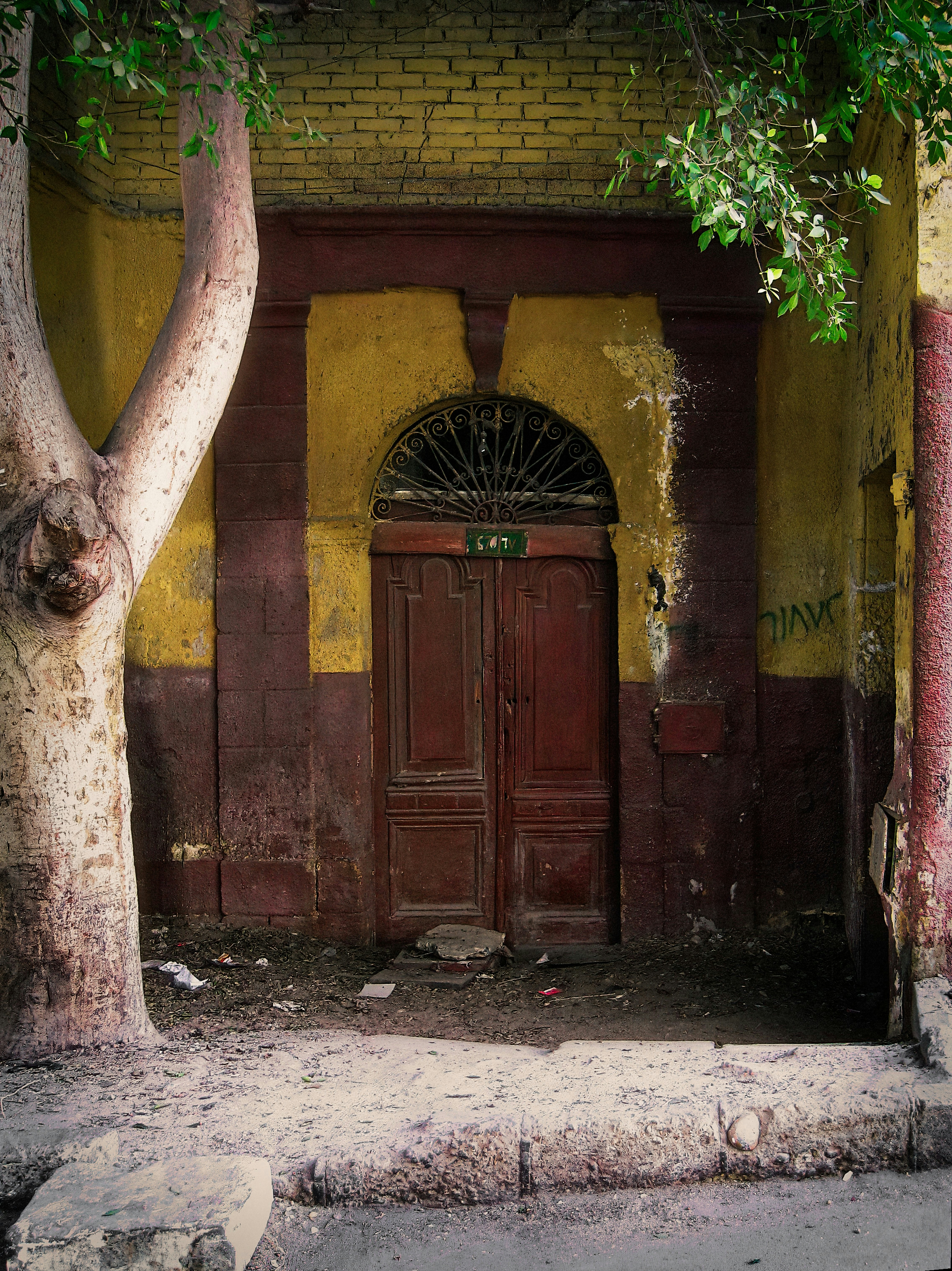 Weathered Archway: A Red Double Door Framed by Yellow and Maroon Facade