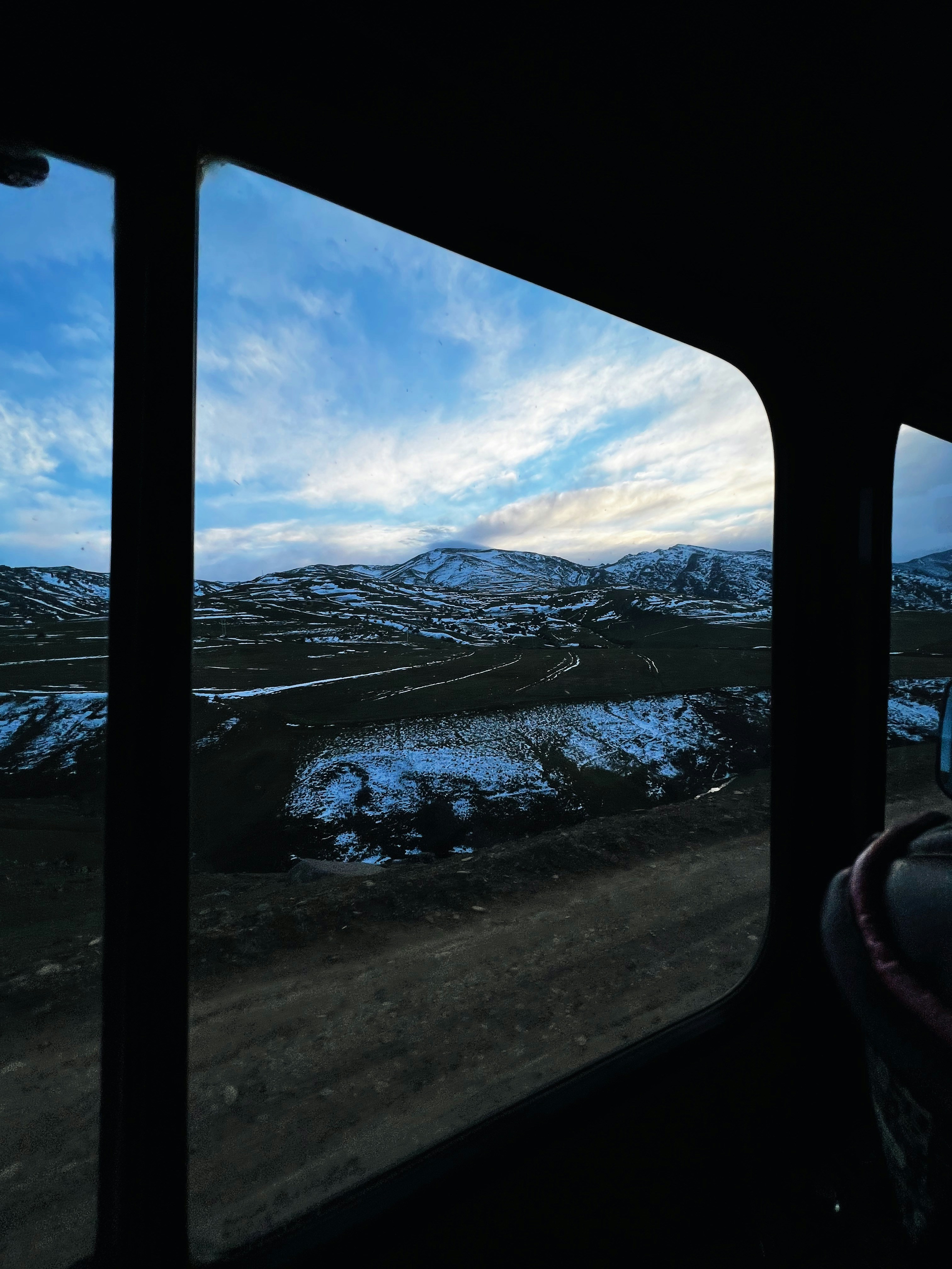 Blue Hour Over Snow-Wrapped Ridges Seen Through a Window Frame