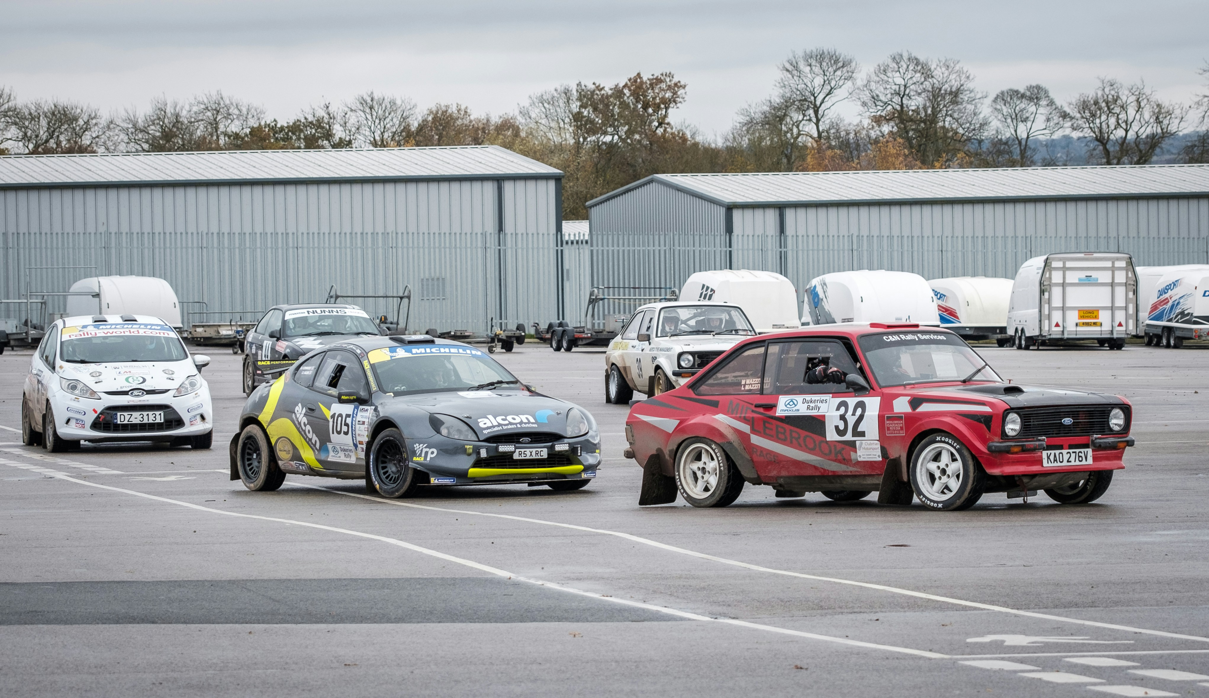 Two Classic Race Cars Idle on a Quiet Paddock Tarmac