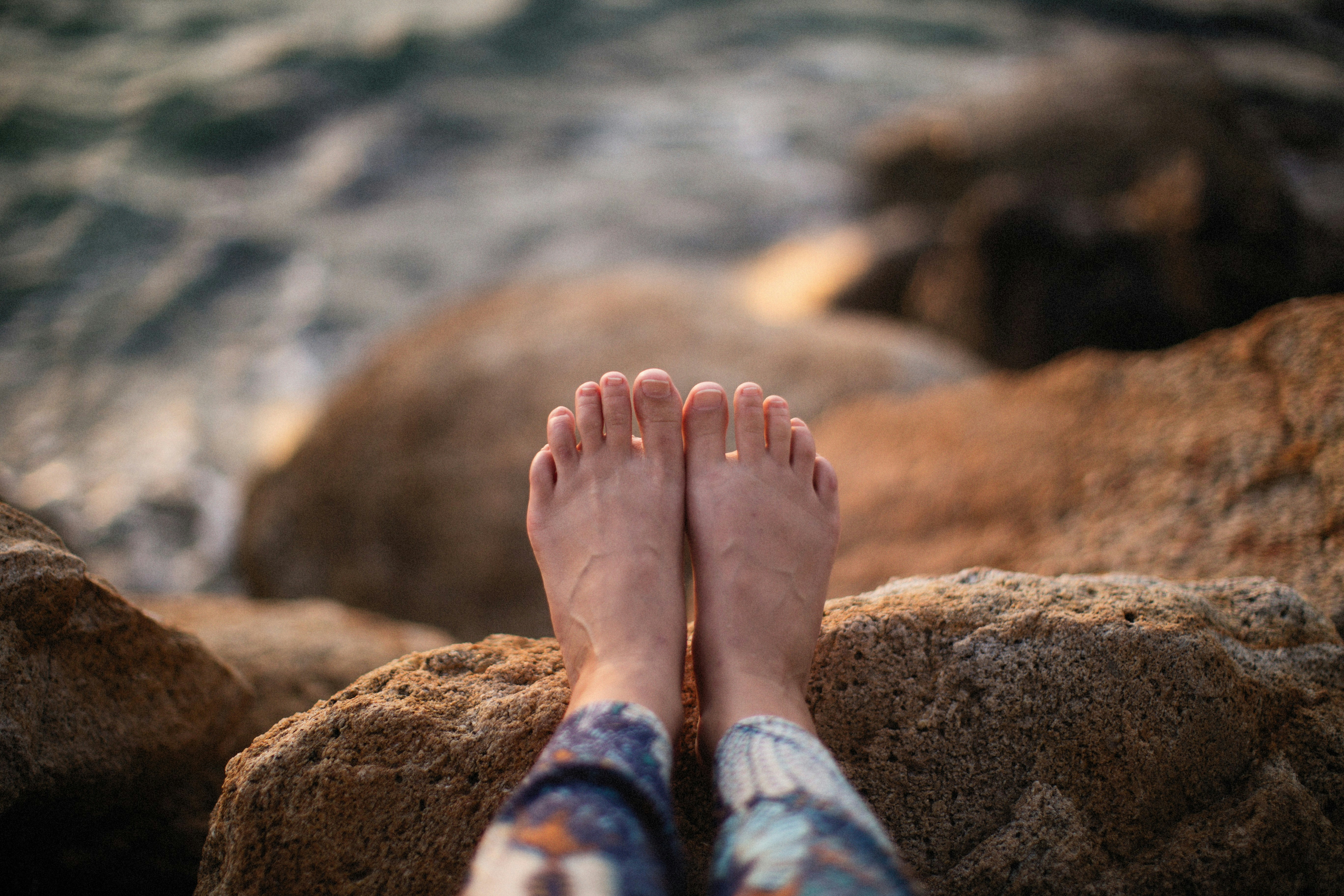 A person sitting on a rock with their feet crossed photo – Free Rock ...