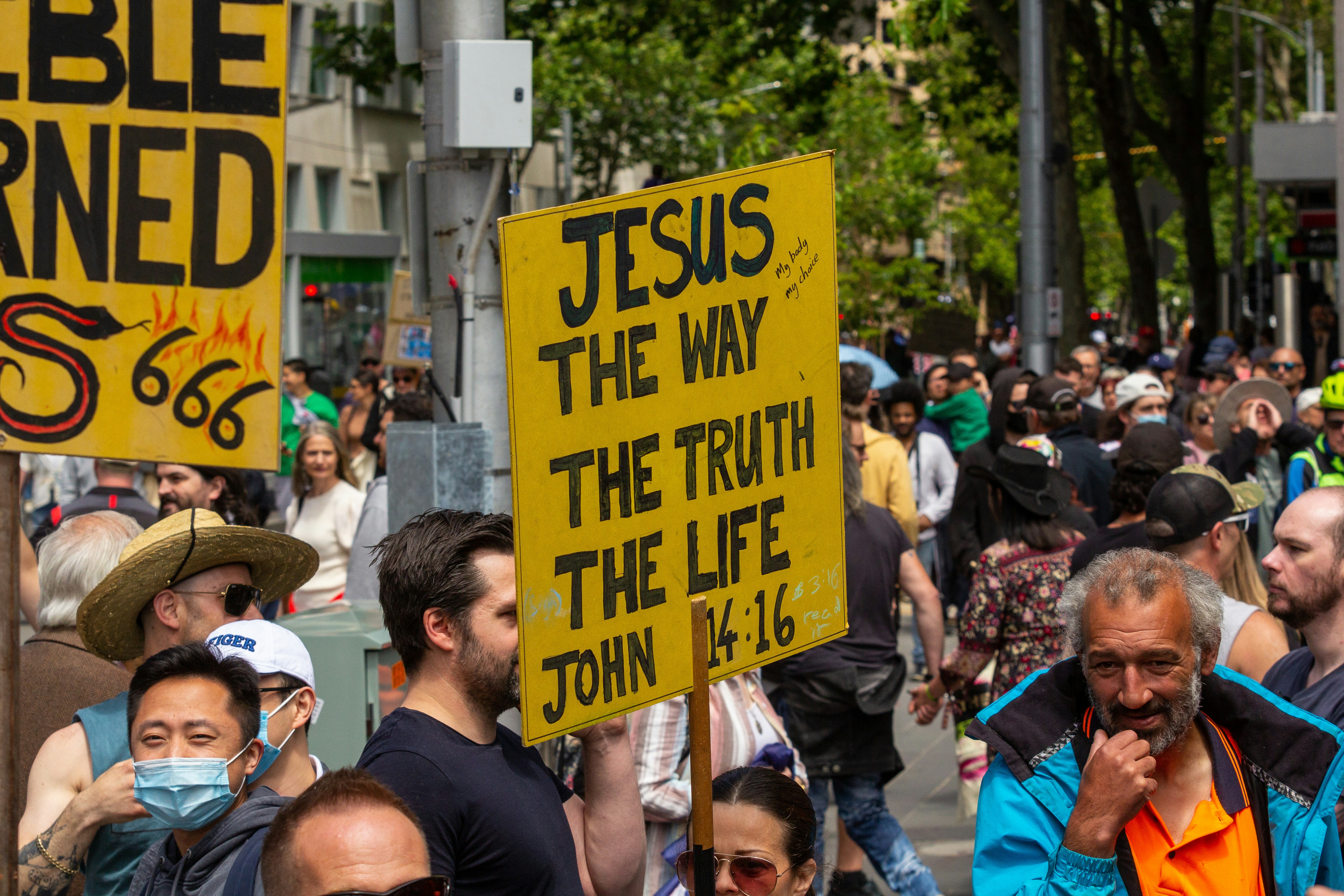 A crowd of people walking down a street holding signs photo – Free ...