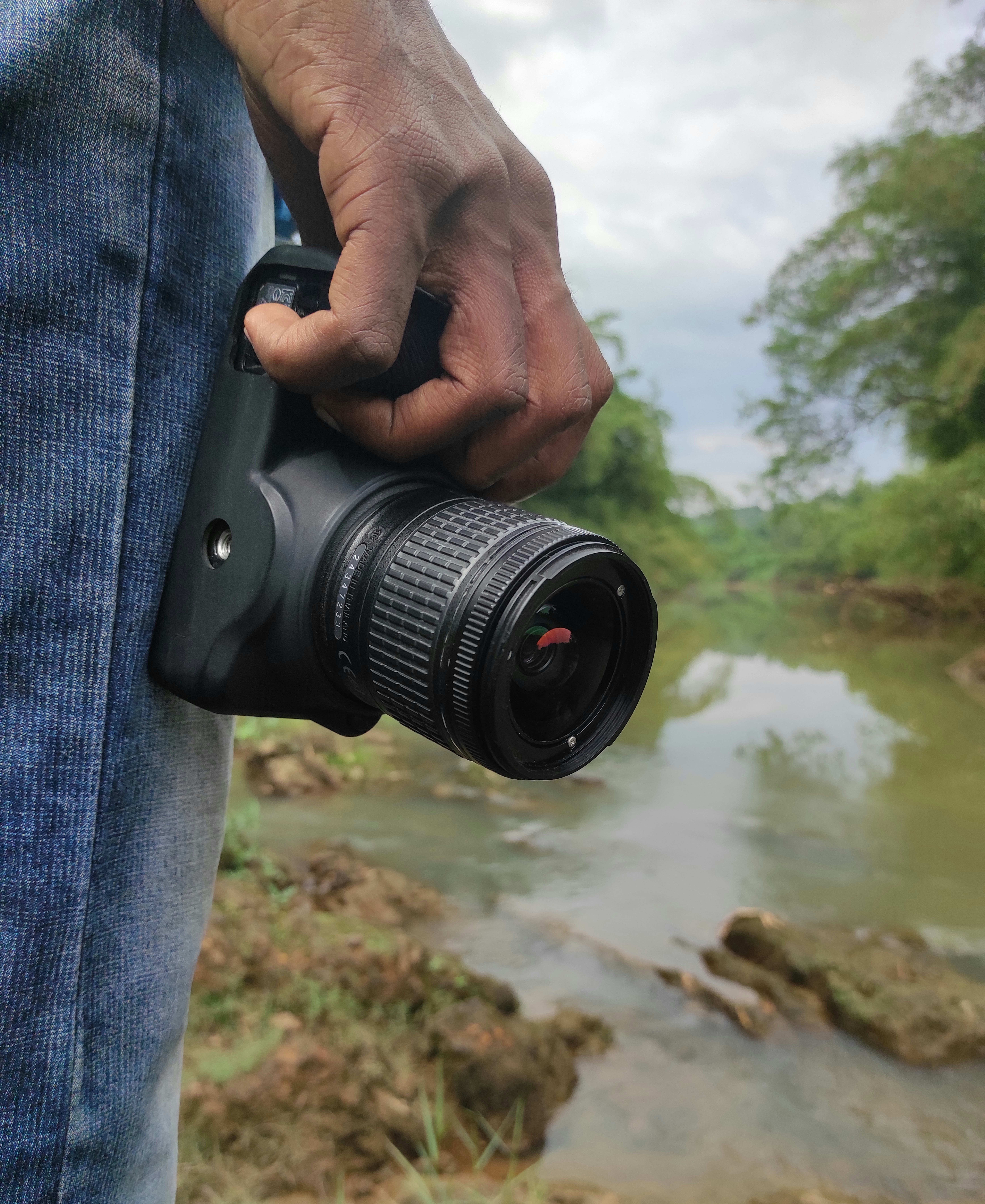 Caught in Focus: A Photographer’s Grip Surrounded by Quiet Stream Reflections