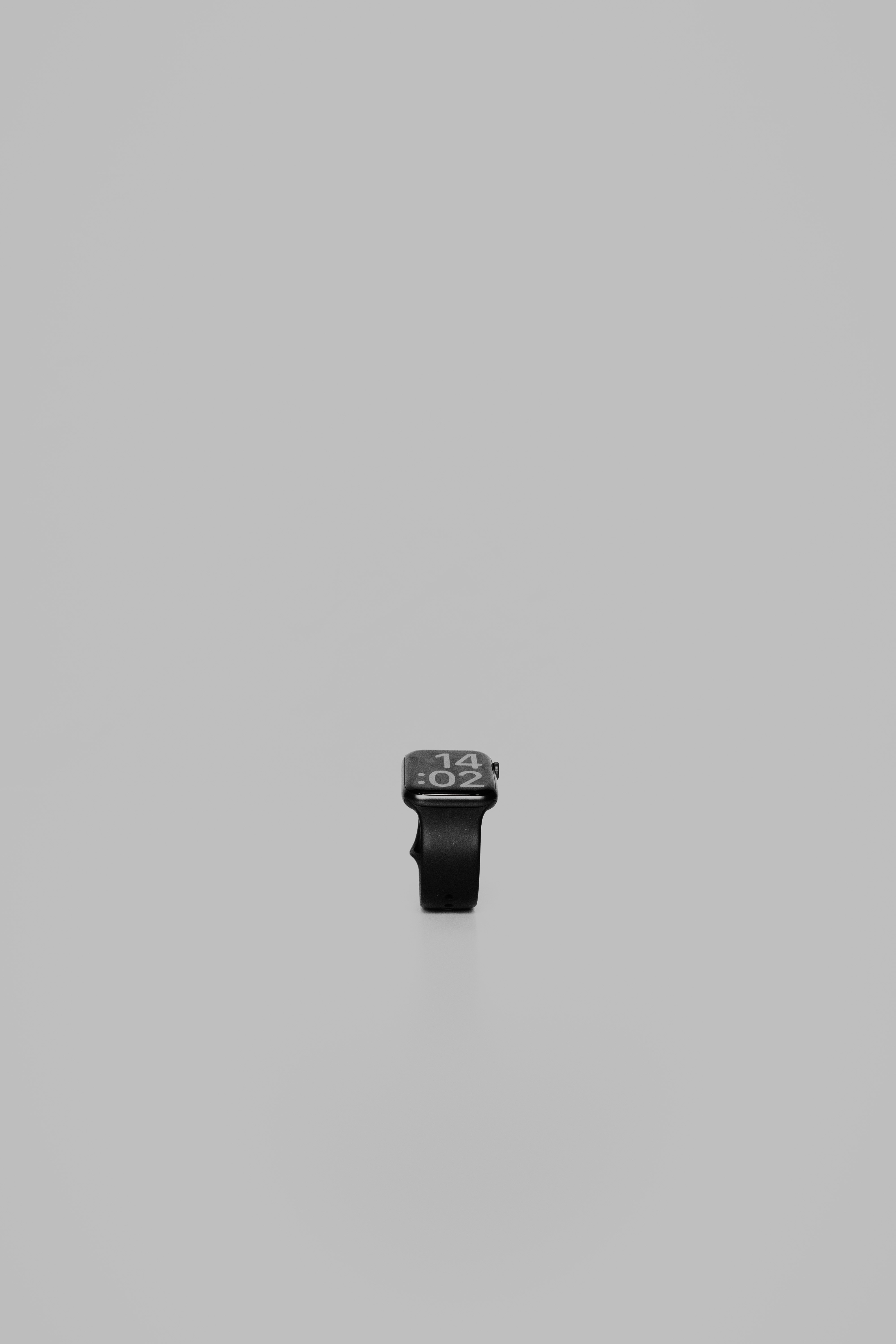 Sleek black wristwatch featuring a unique digital display, emphasizing minimalist aesthetics against a soft gray background.