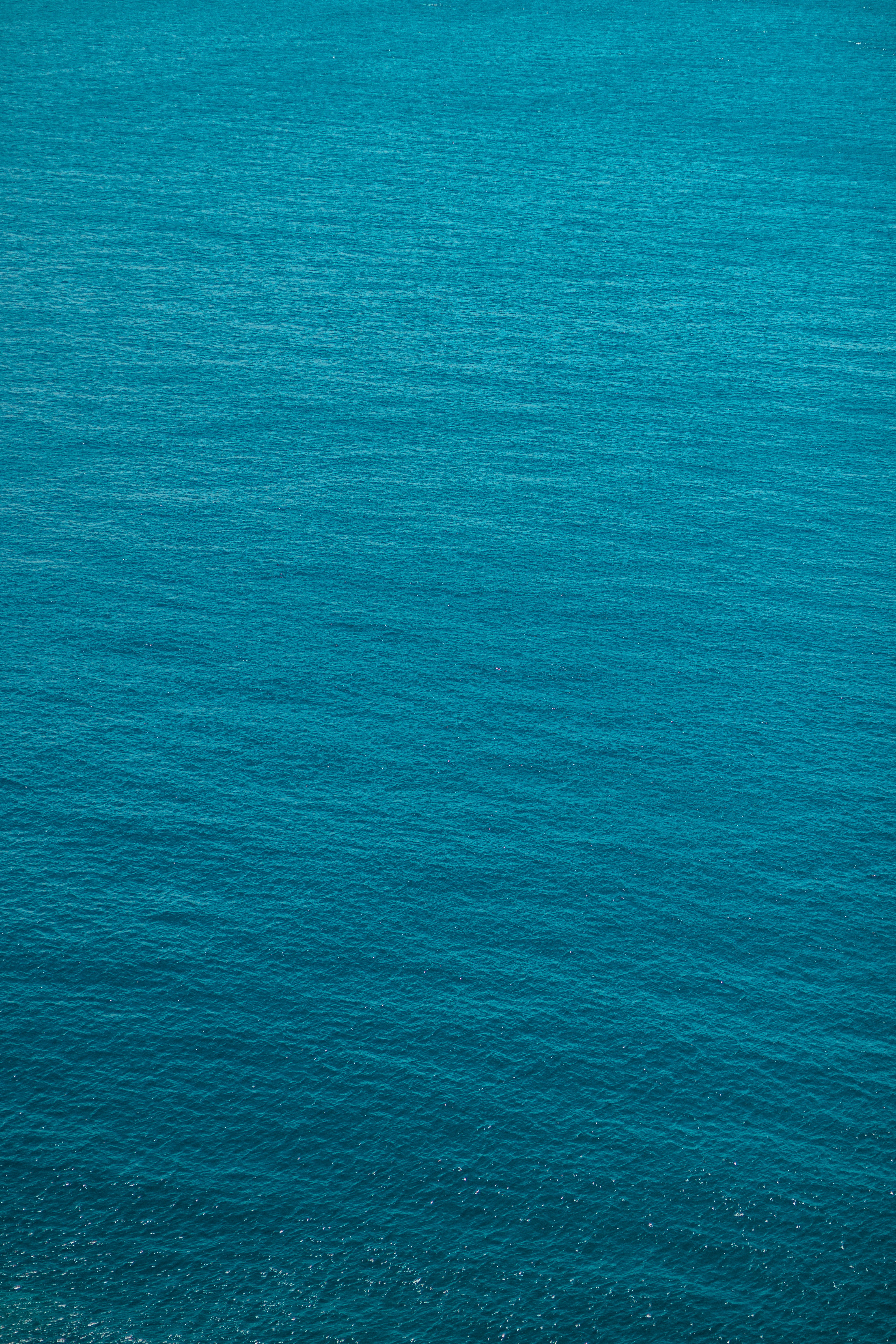 Vast expanse of tranquil aquamarine water reflecting sunlight, creating a serene atmosphere.