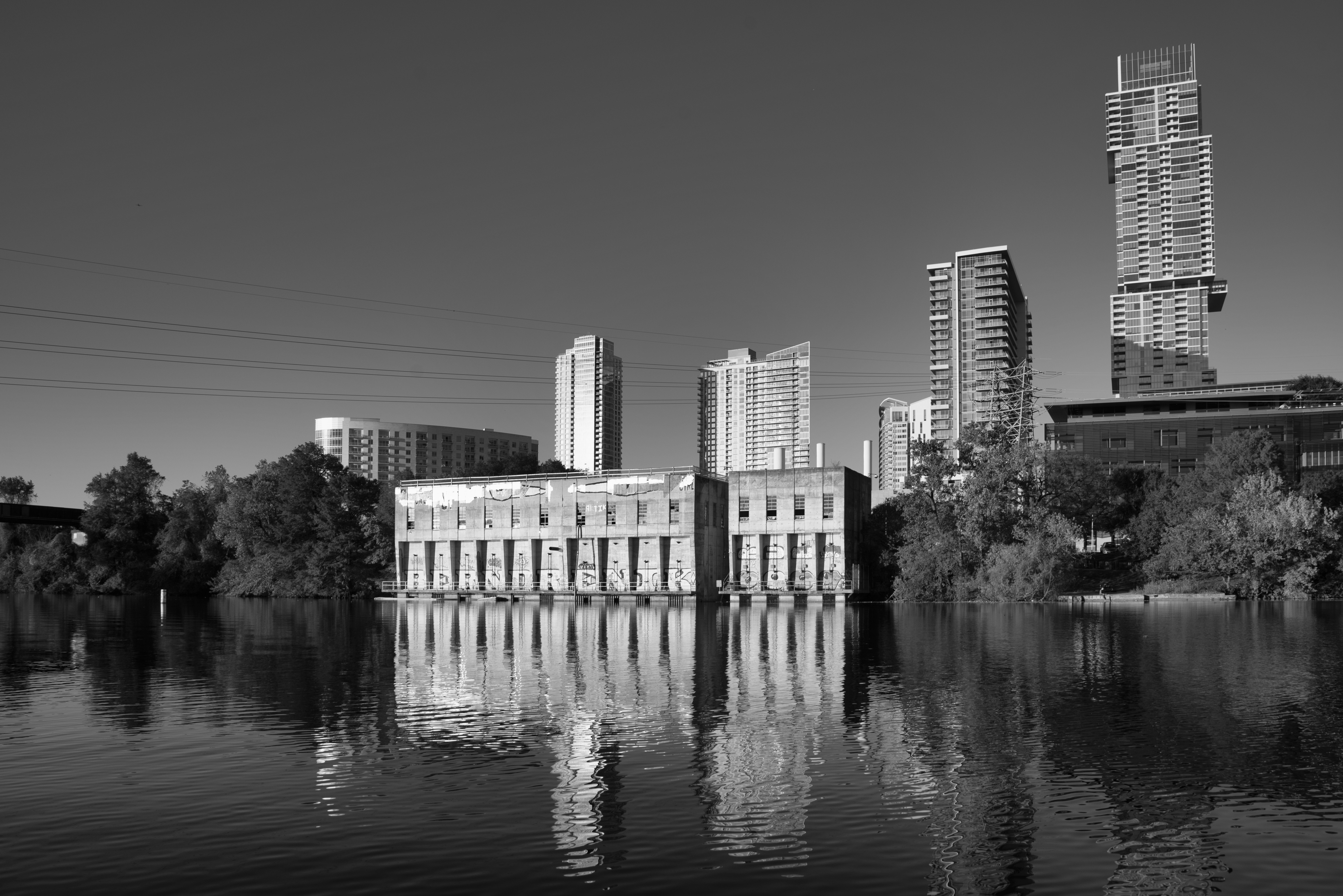 Historic building reflecting in calm waters with modern skyline in the background.