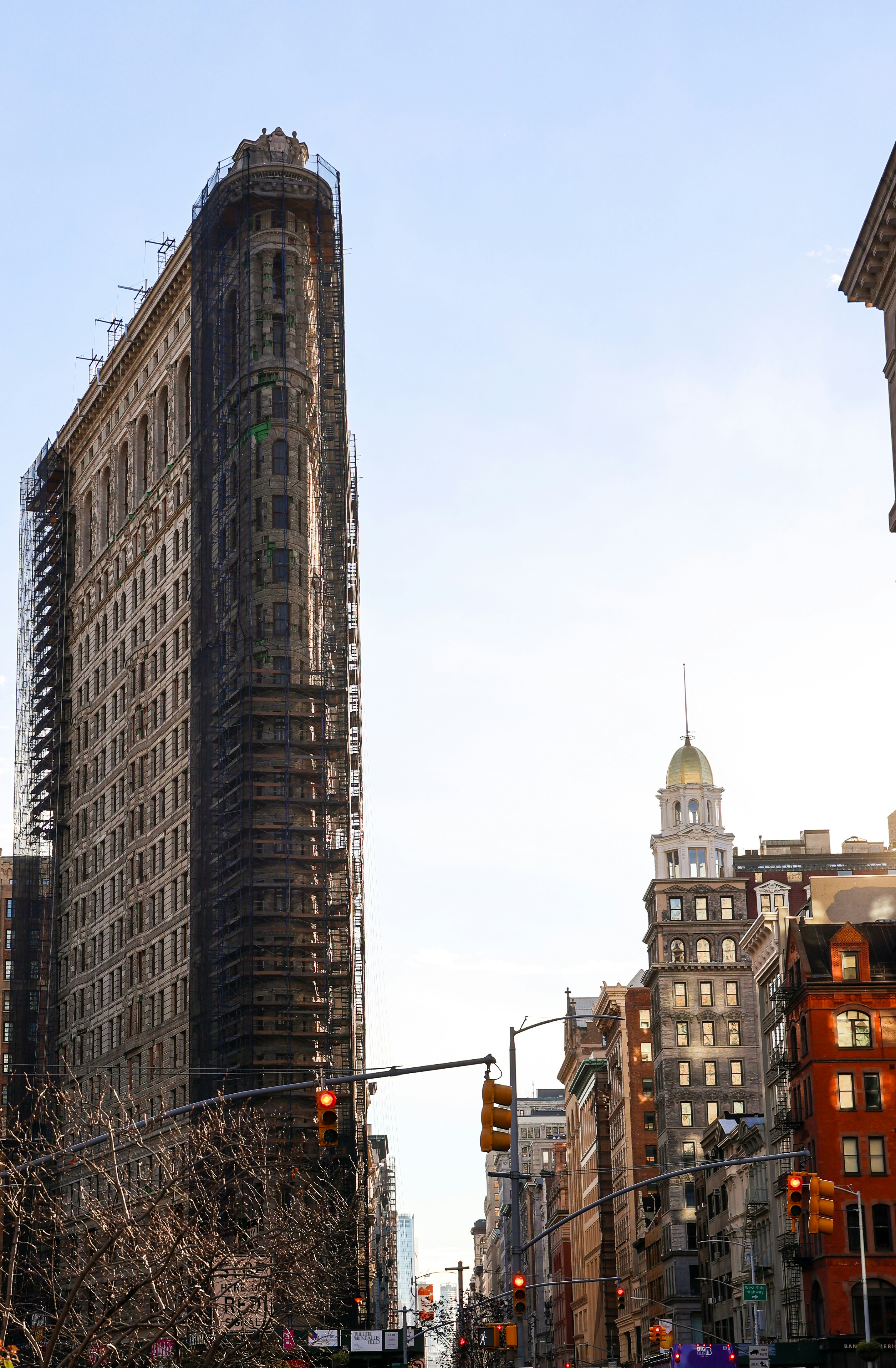 Rising Skeleton: A scaffold-wrapped tower anchors a sunlit city street
