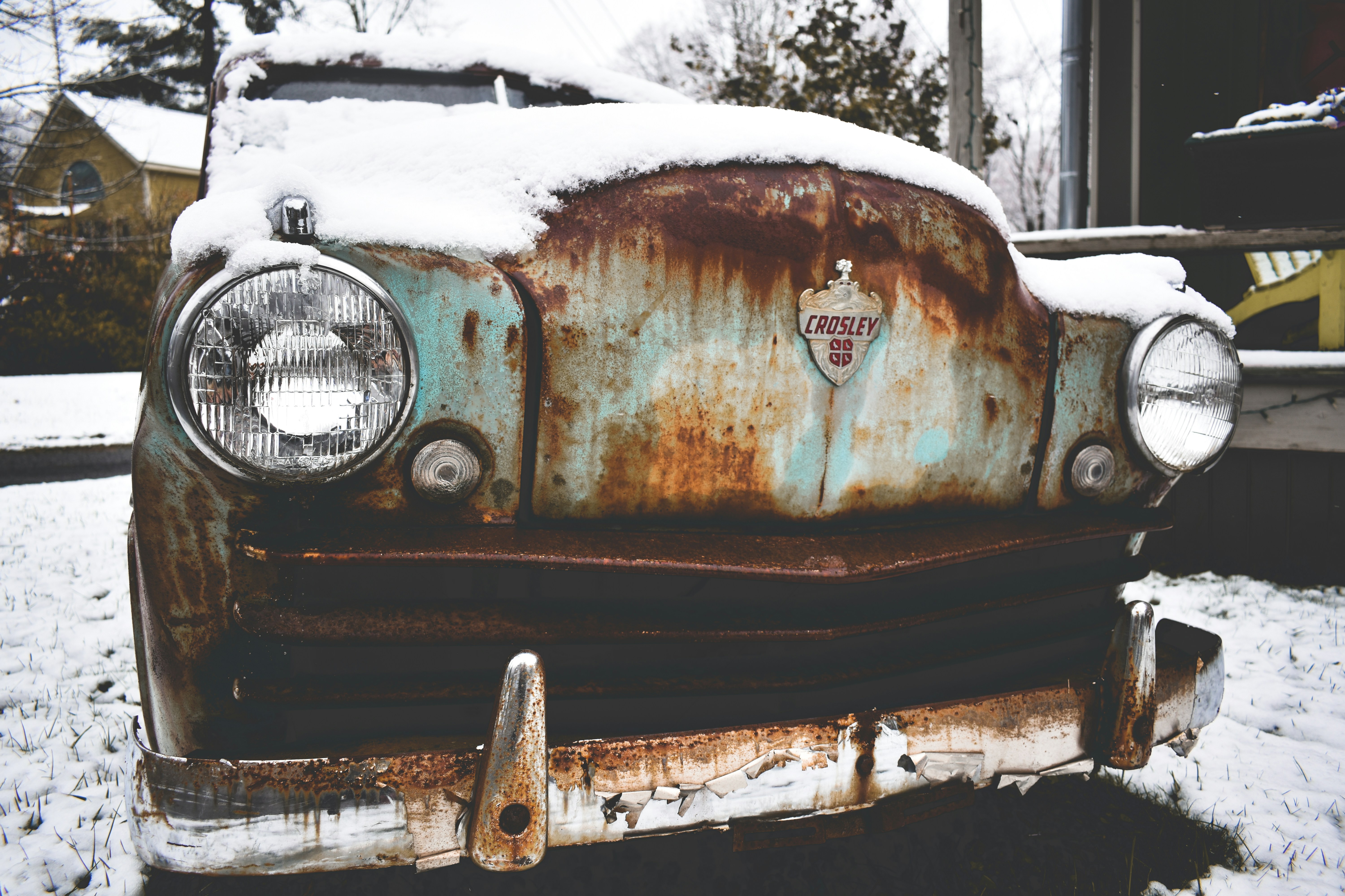 Weathered Crosley car front adorned with snow, showcasing its vintage charm and rustic details.