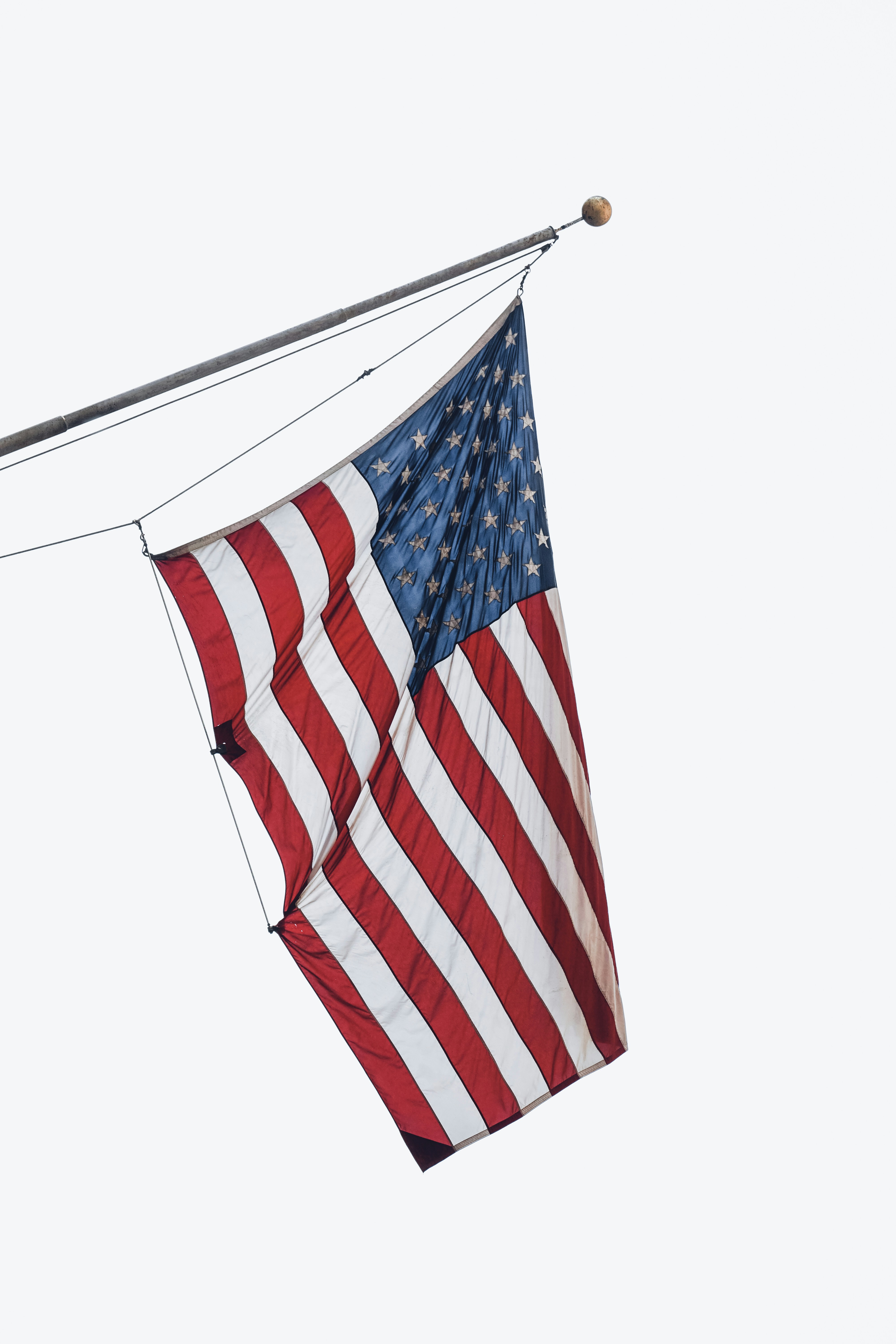 American Flag on a Diagonal Mast Against a Pale Sky