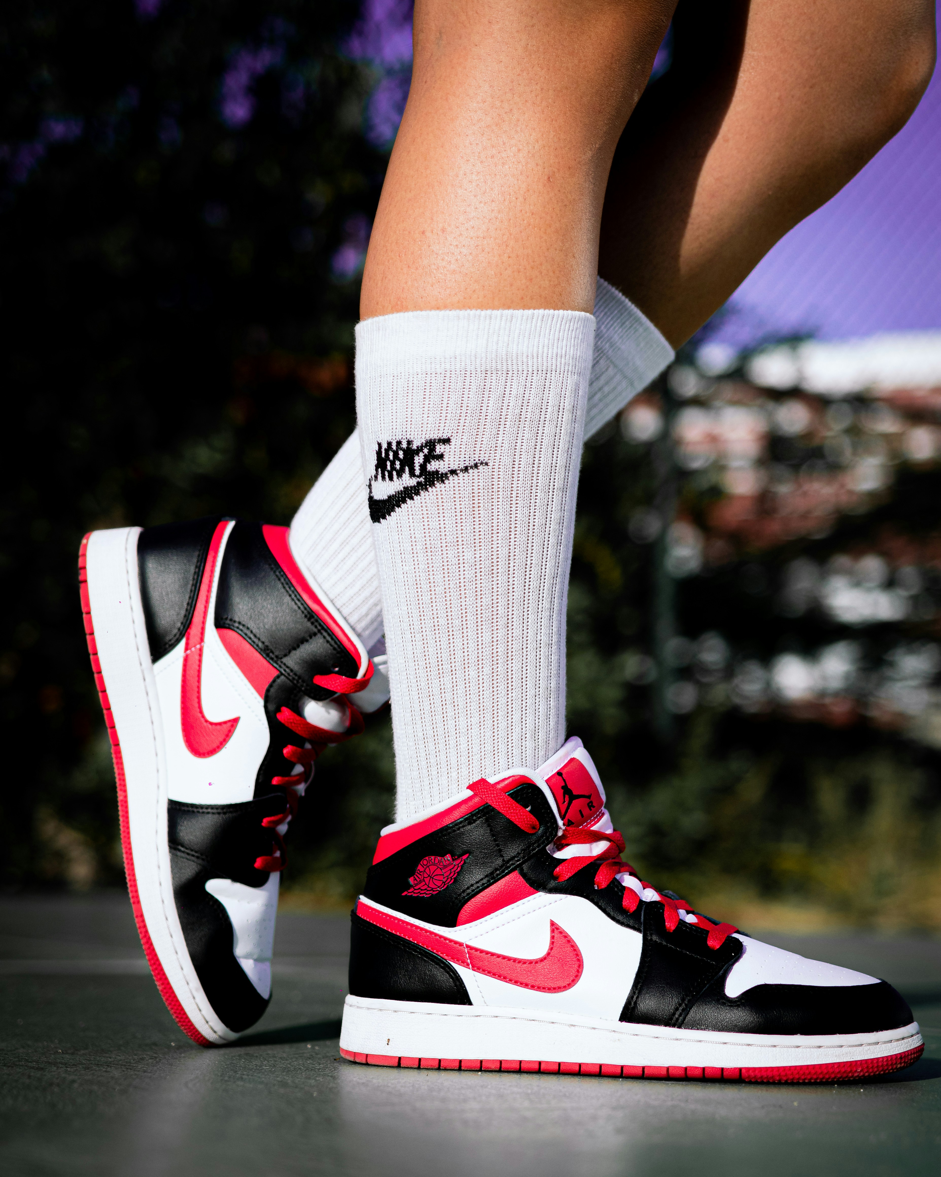 a person wearing a pair of black and red sneakers