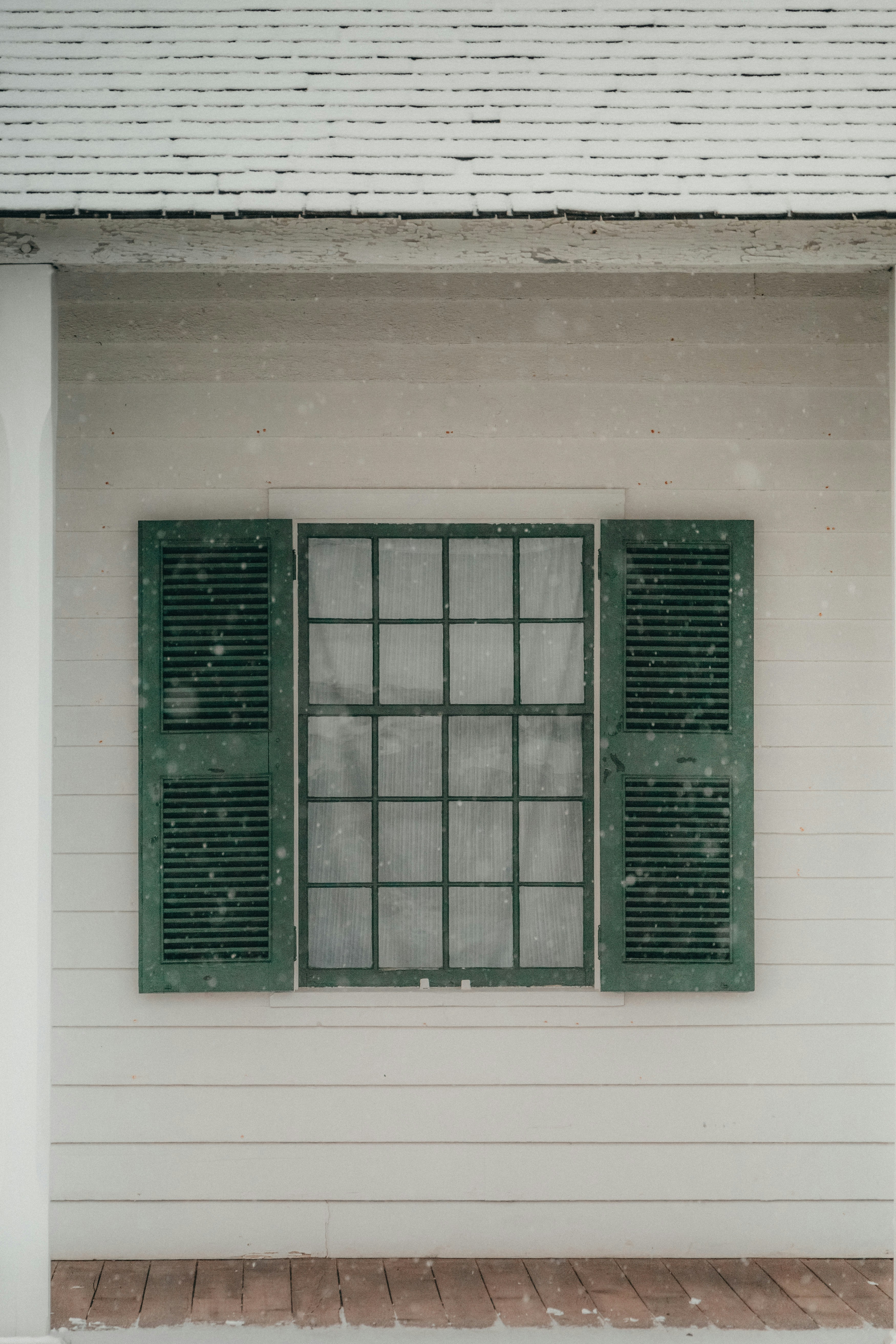 Winter Window Grid: A Green-Shuttered Frame in Snow