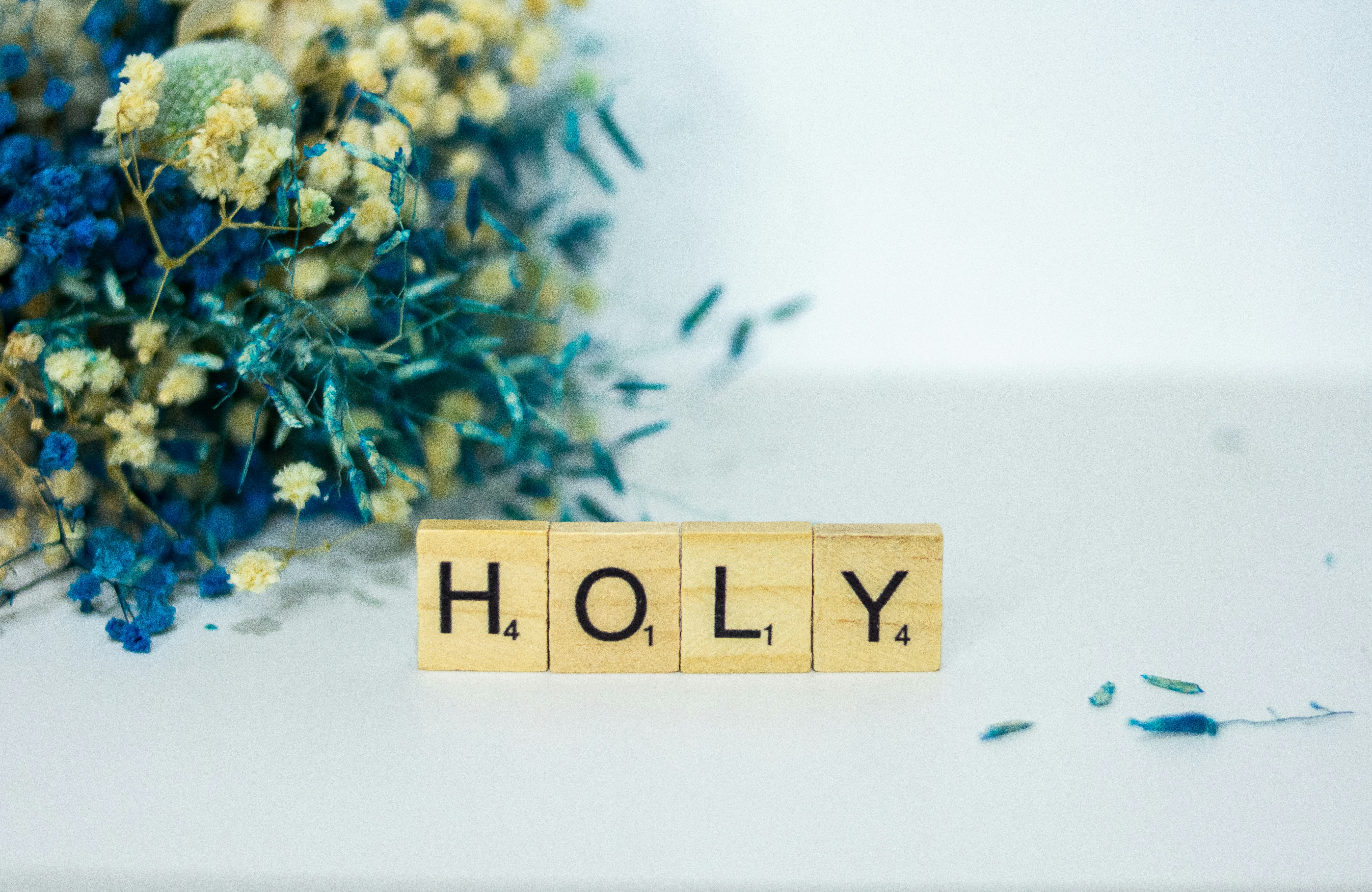 A wooden block spelling the word holly next to a bouquet of flowers ...