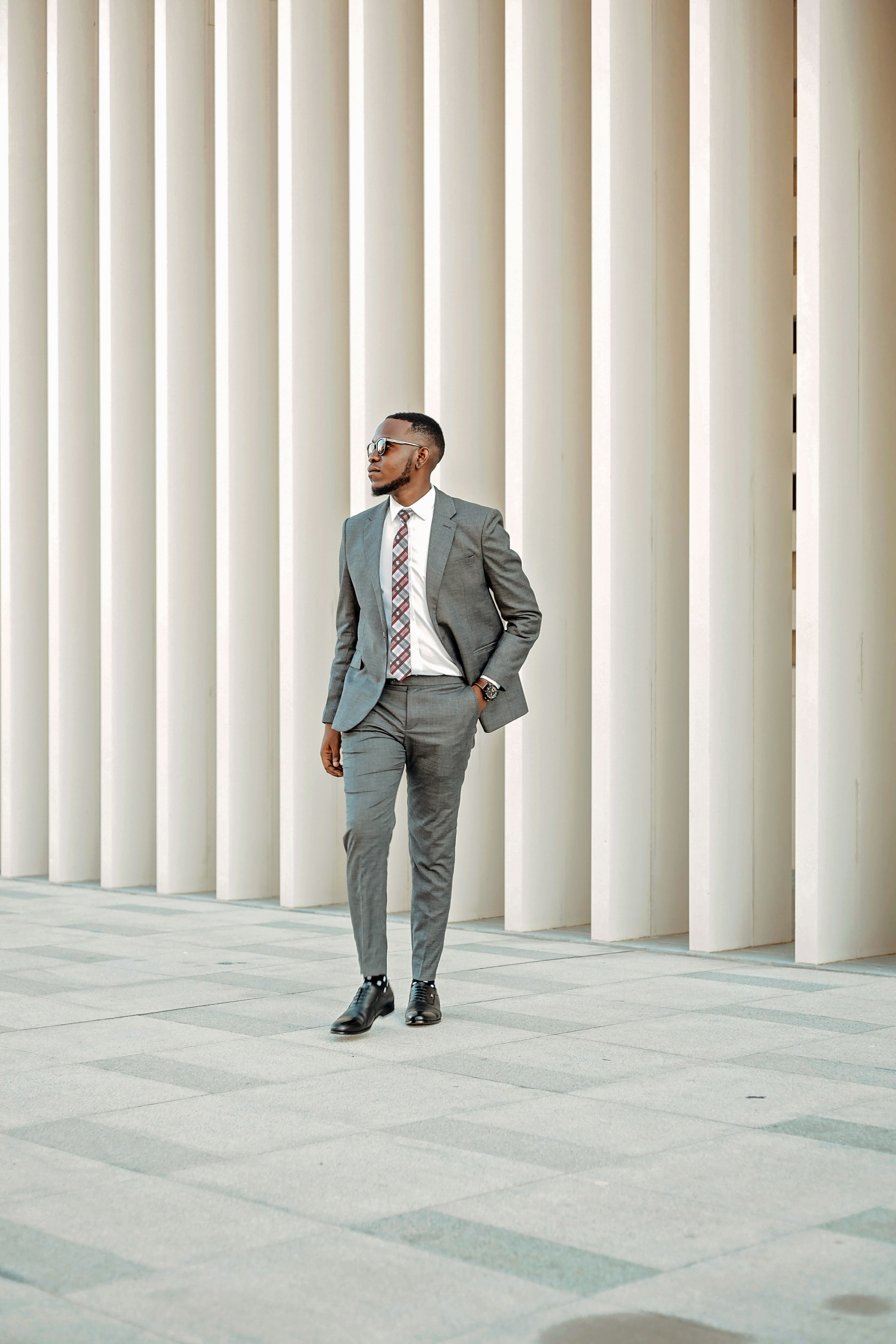 A man in a suit and tie standing in front of columns photo – Free ...