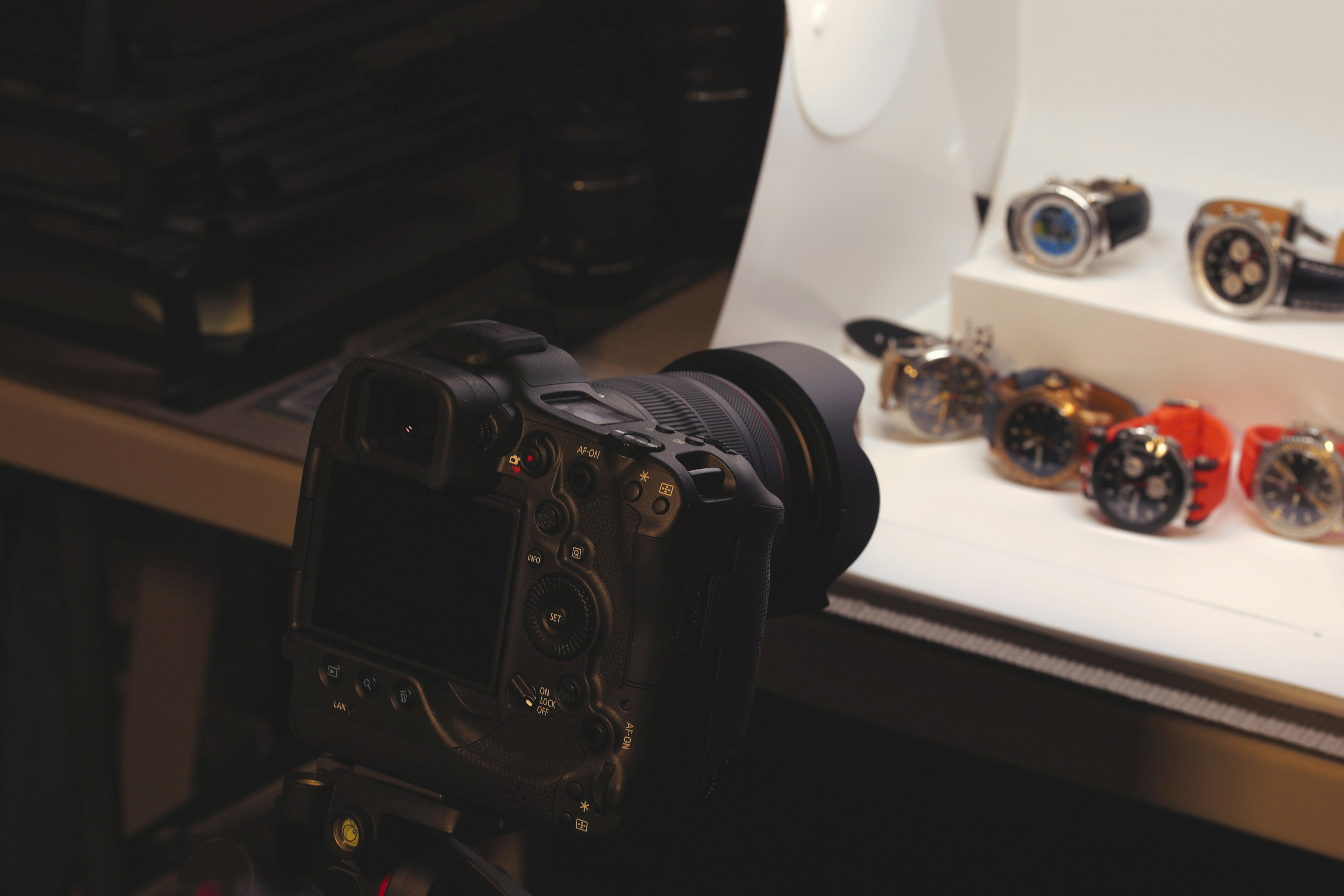 A camera is sitting on a tripod in front of a display of watches photo ...