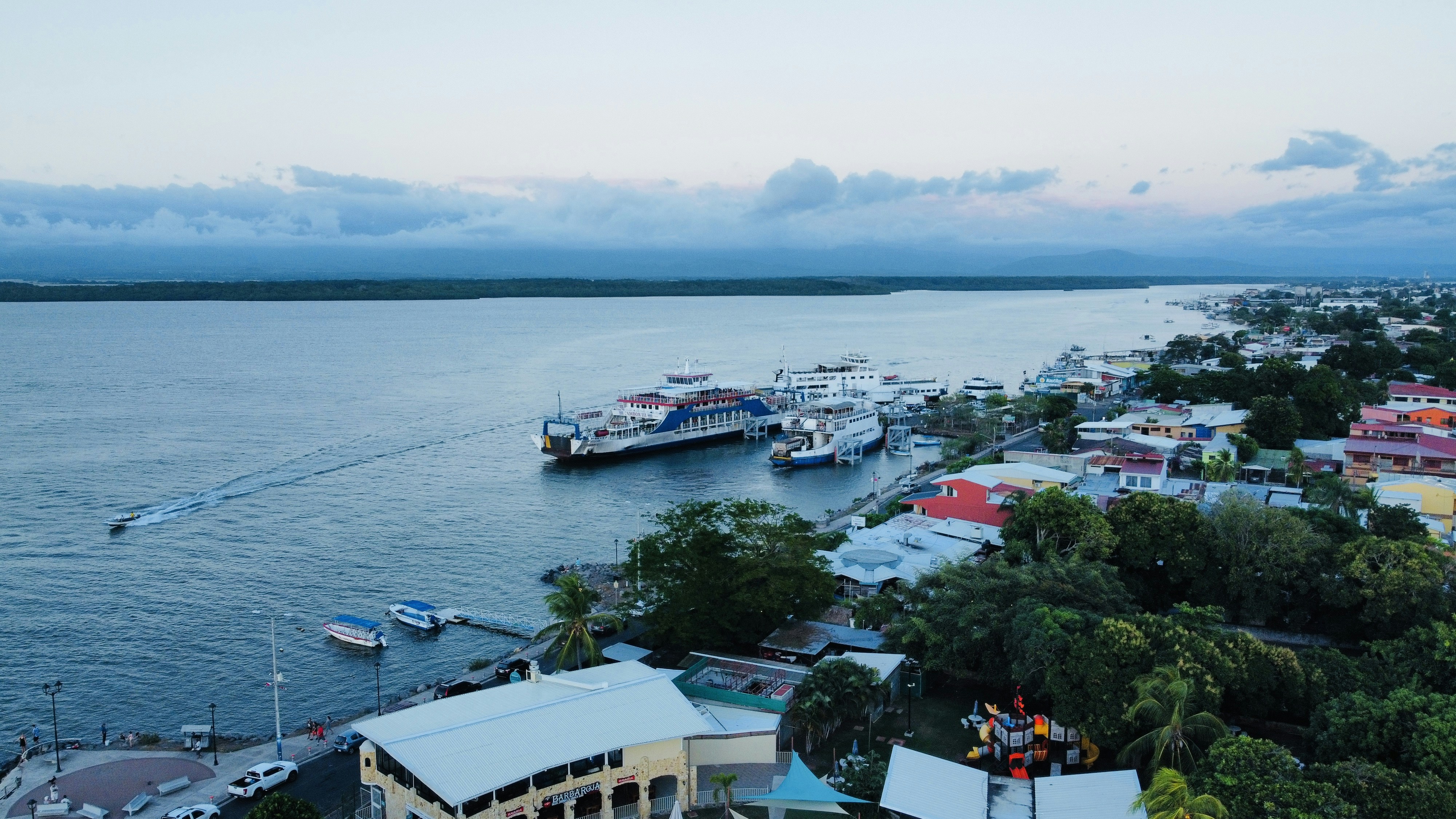 Aerial view of a bustling harbor with boats docked and colorful buildings lining the shore, showcasing the vibrant life along the water's edge.