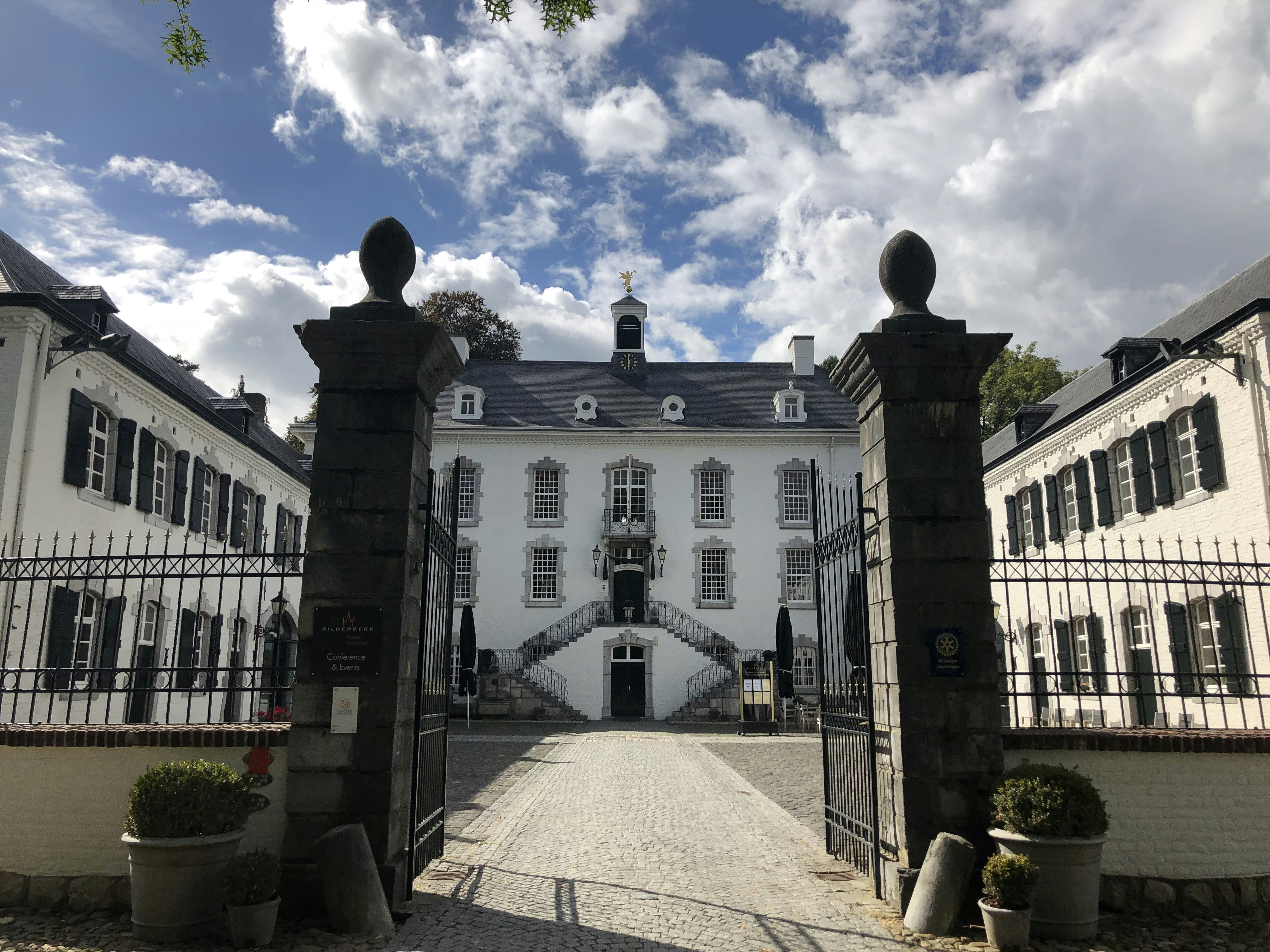 Grand entrance of a historic castle with symmetrical architecture under a partly cloudy sky.