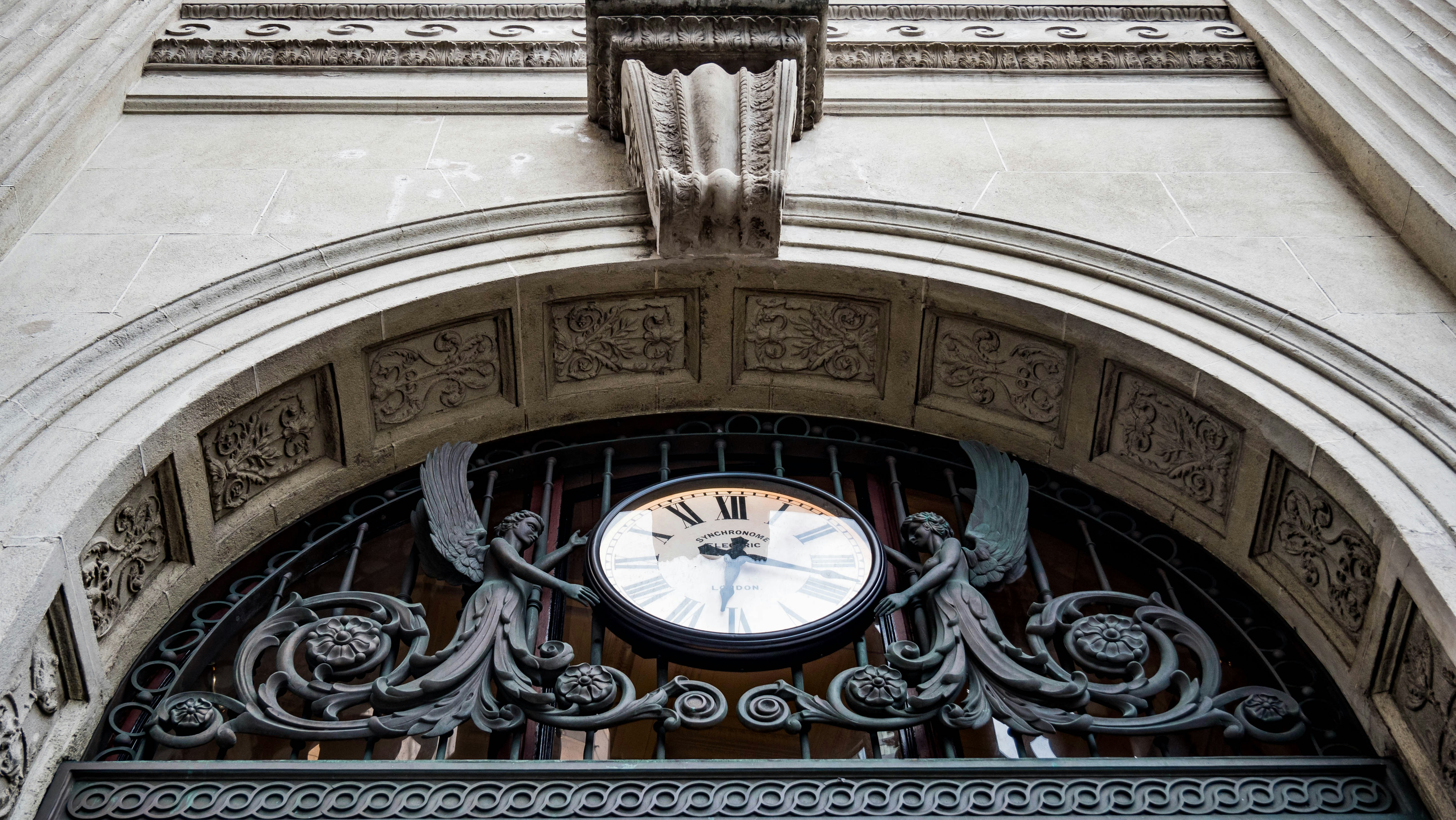 A clock mounted to the side of a building photo – Free Architecture ...