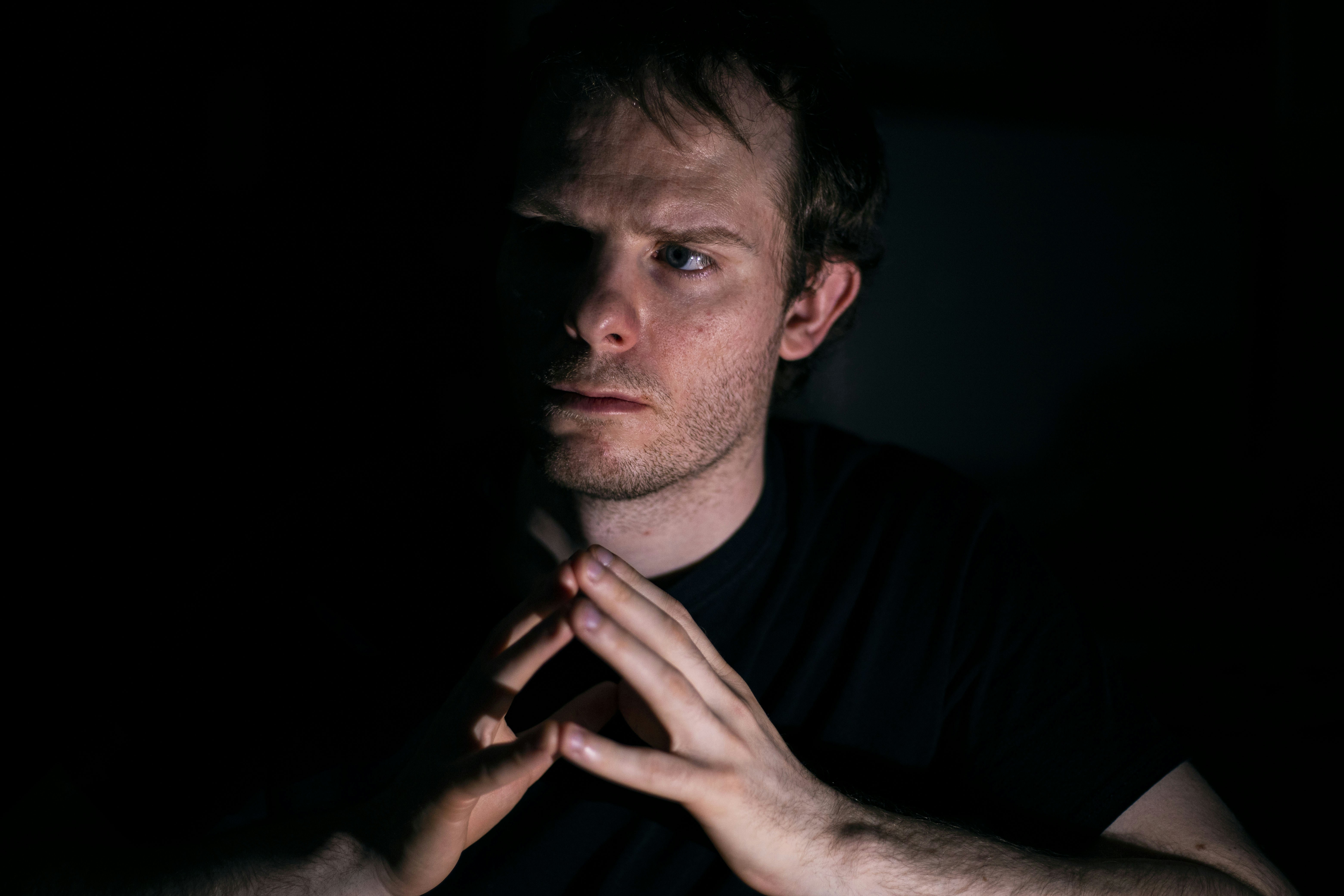 Half-Light Contemplation: A Portrait with Shadowed Gaze and Folded Hands