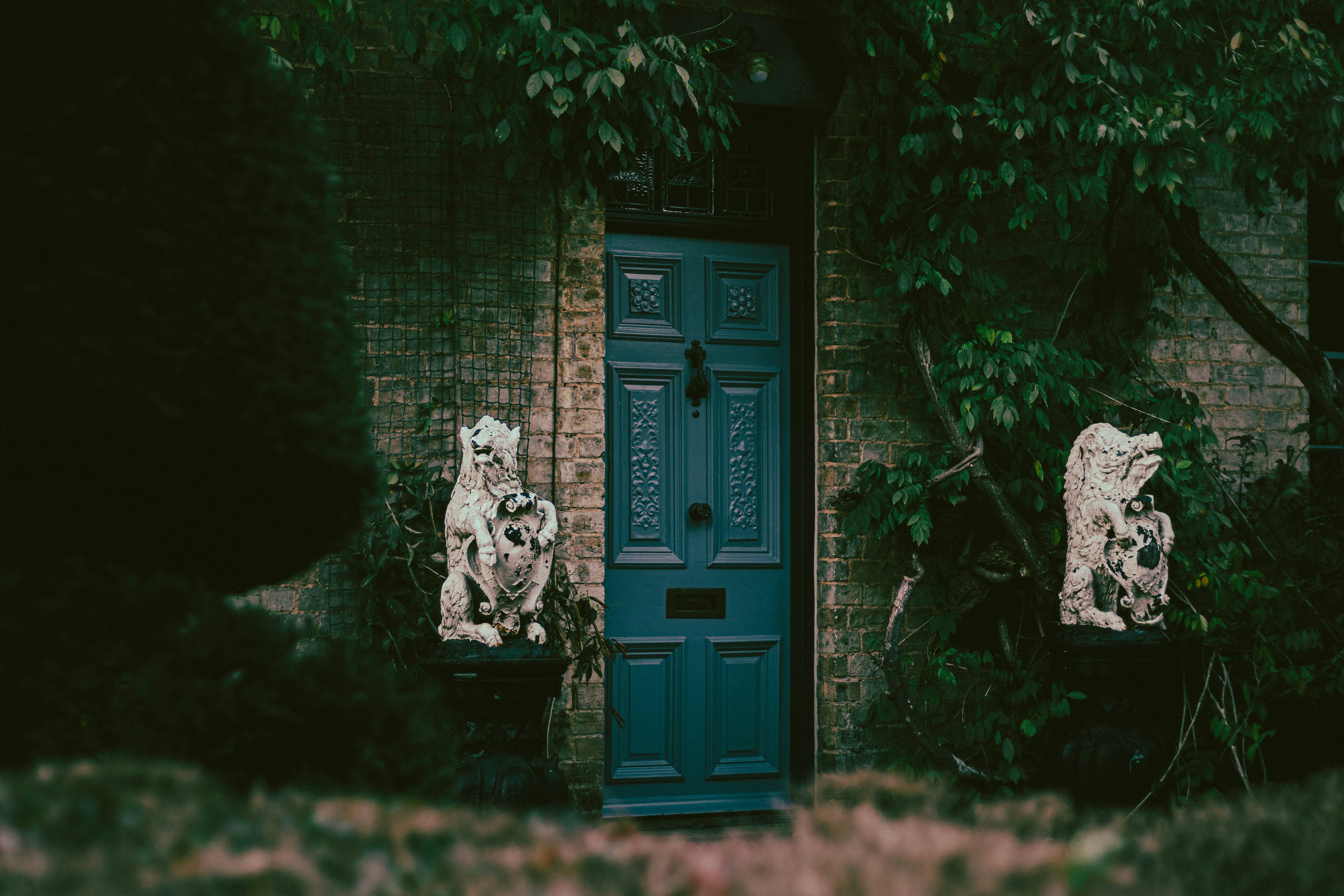Azure Doorway Framed by Ivy and Stone Lions in a Shadowed Brick Façade