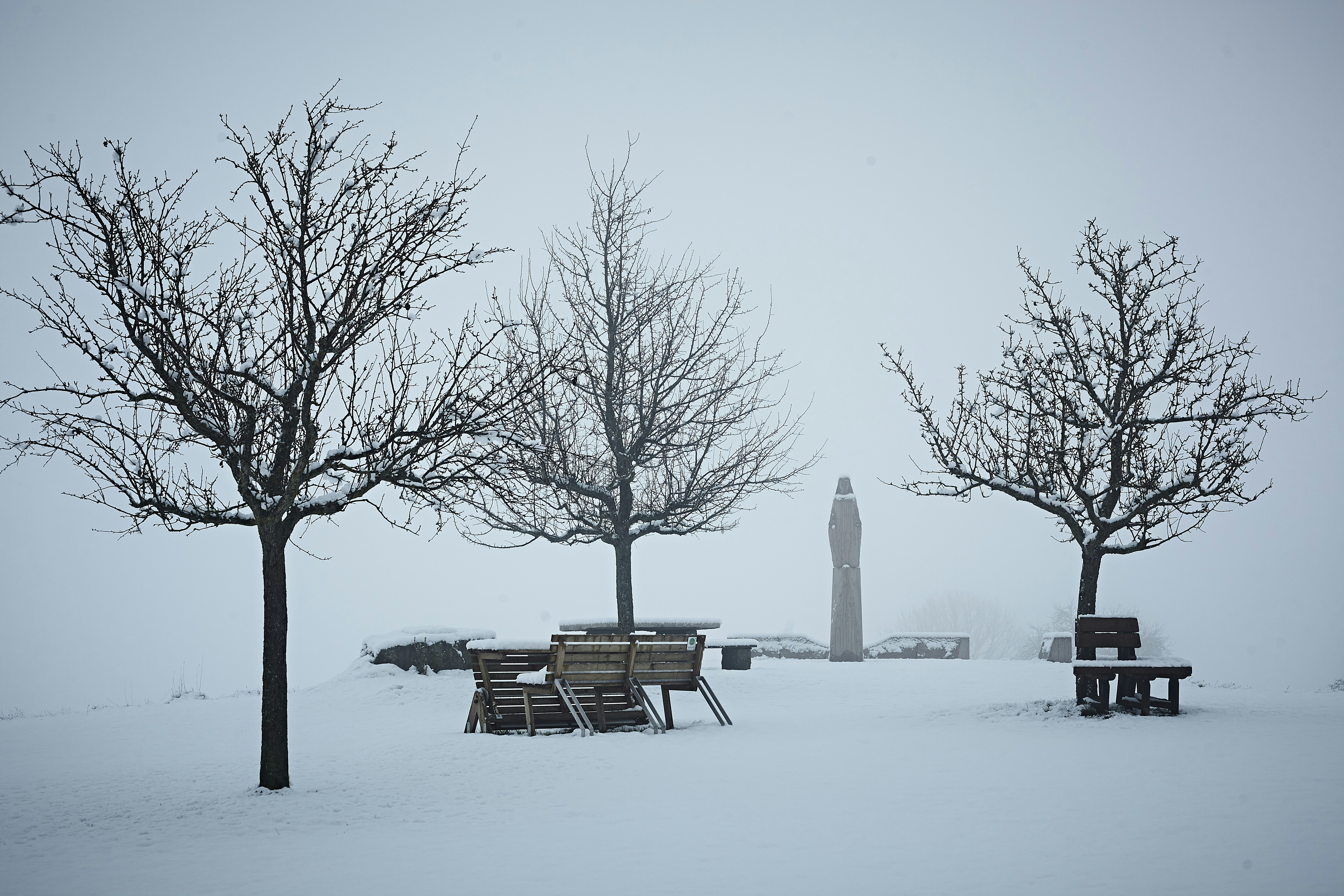 a park bench and table covered in snow