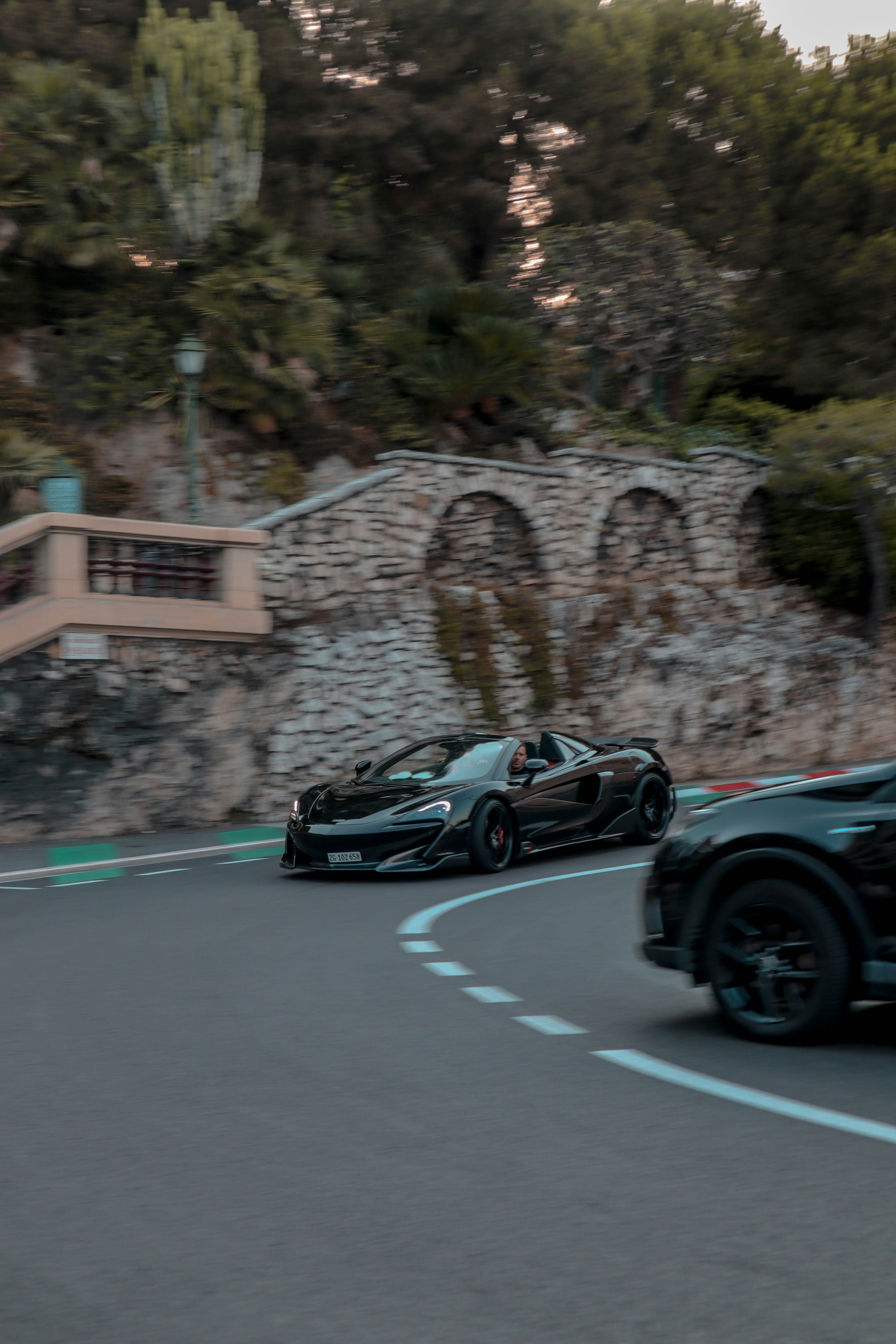 Foto Un par de coches conduciendo por una carretera con curvas – Imagen ...