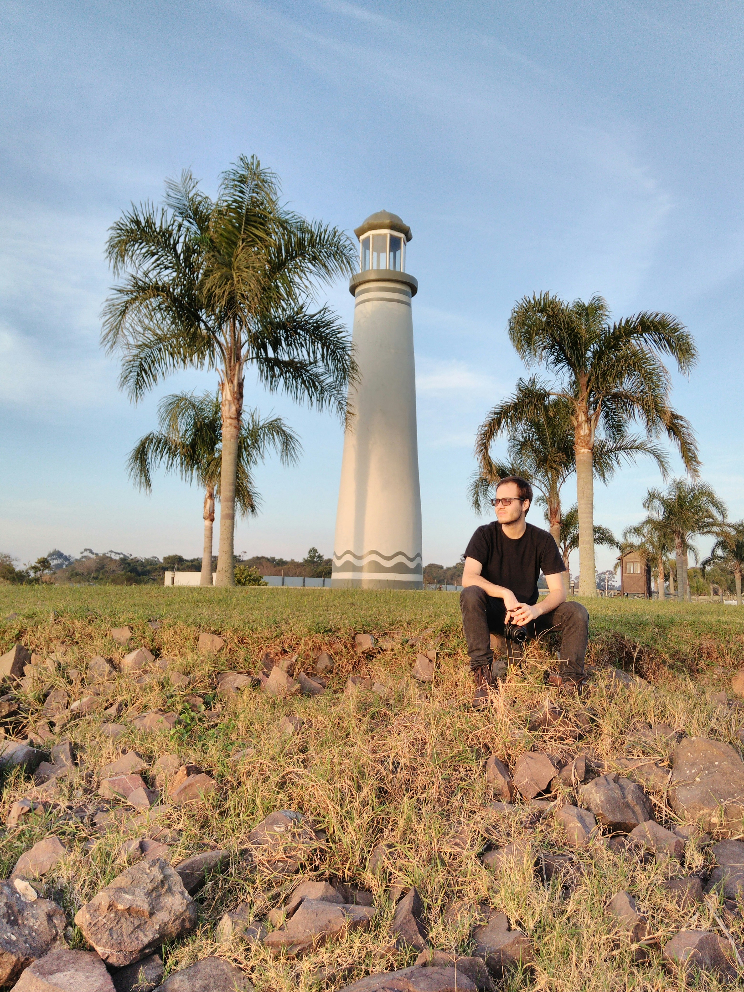 a man sitting in a field next to a light house