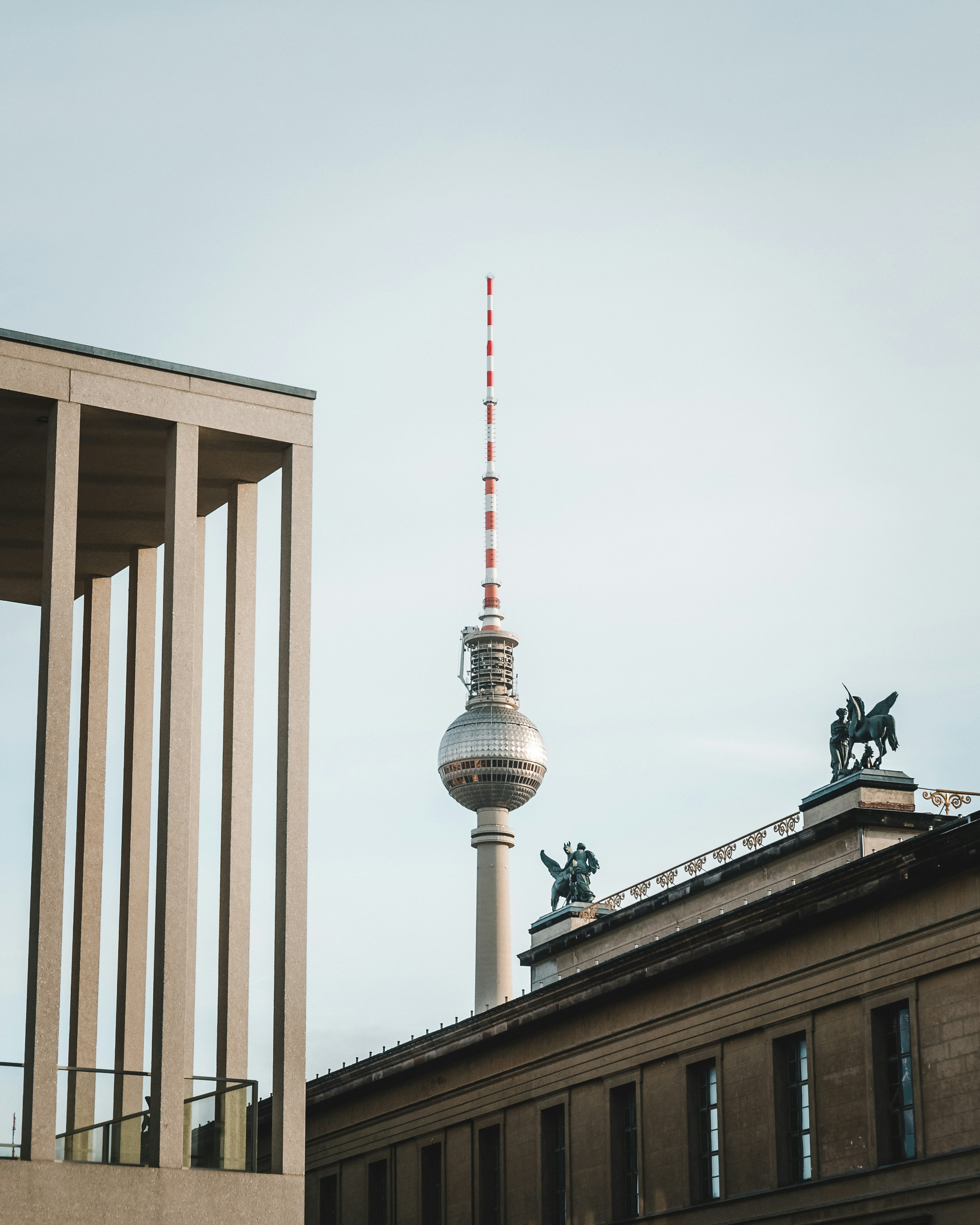Berlin's Needle Over Marble and Steel: Fernsehturm Framed by Rooftop Statues