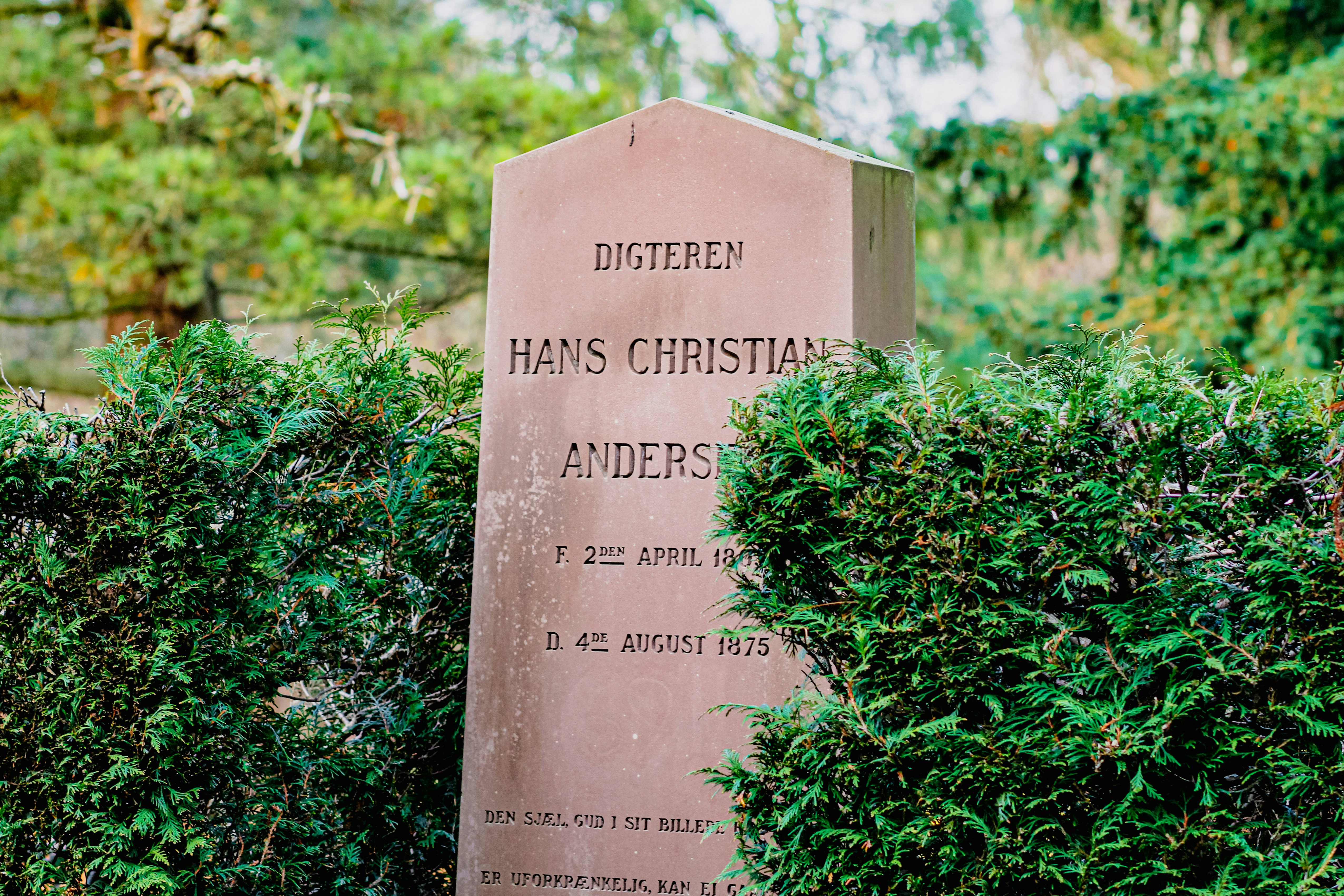 Gravestone of Hans Christian Andersen surrounded by lush greenery, marking the resting place of the famed storyteller.