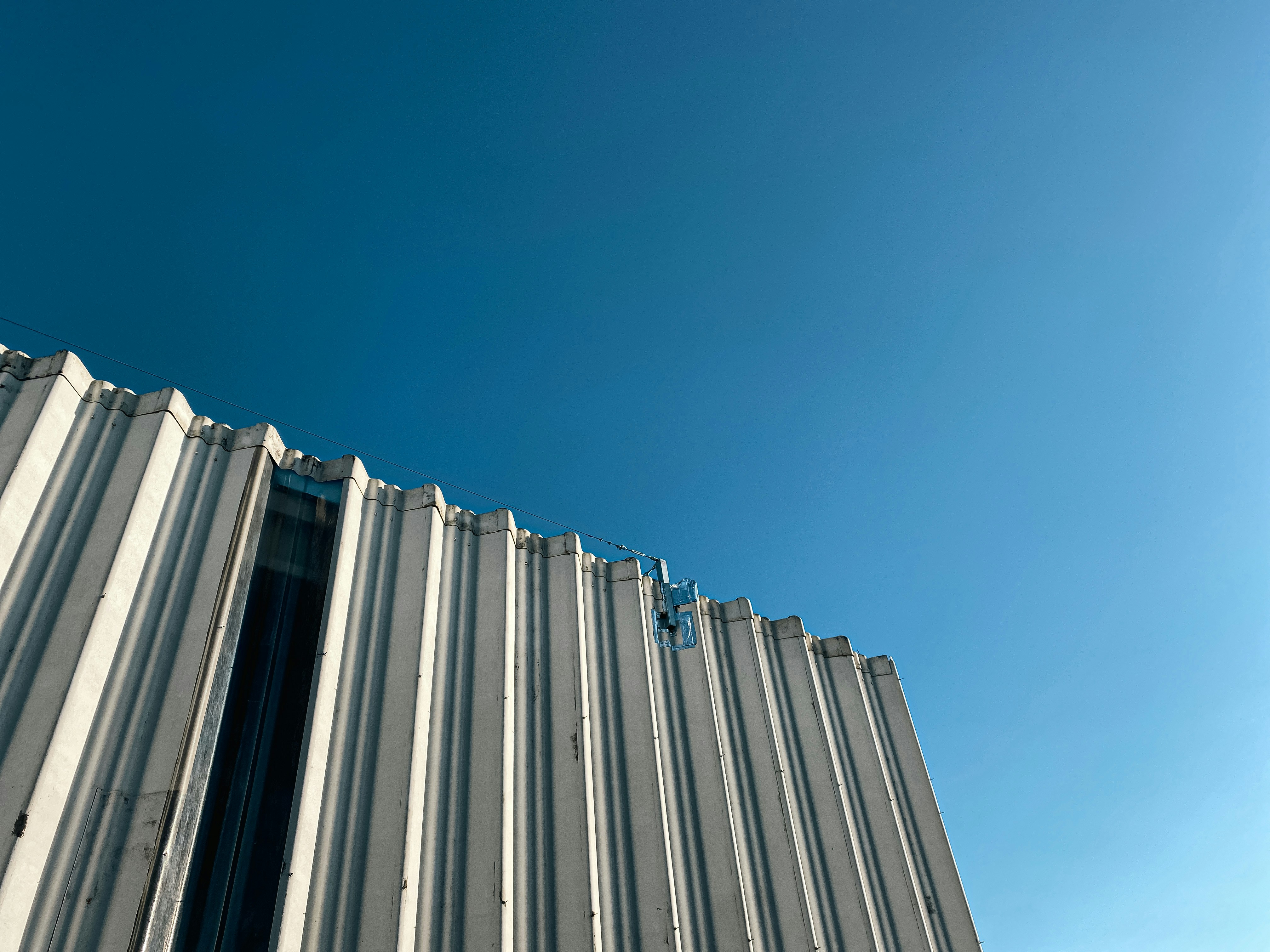 Modern building facade with vertical lines set against a clear blue sky.