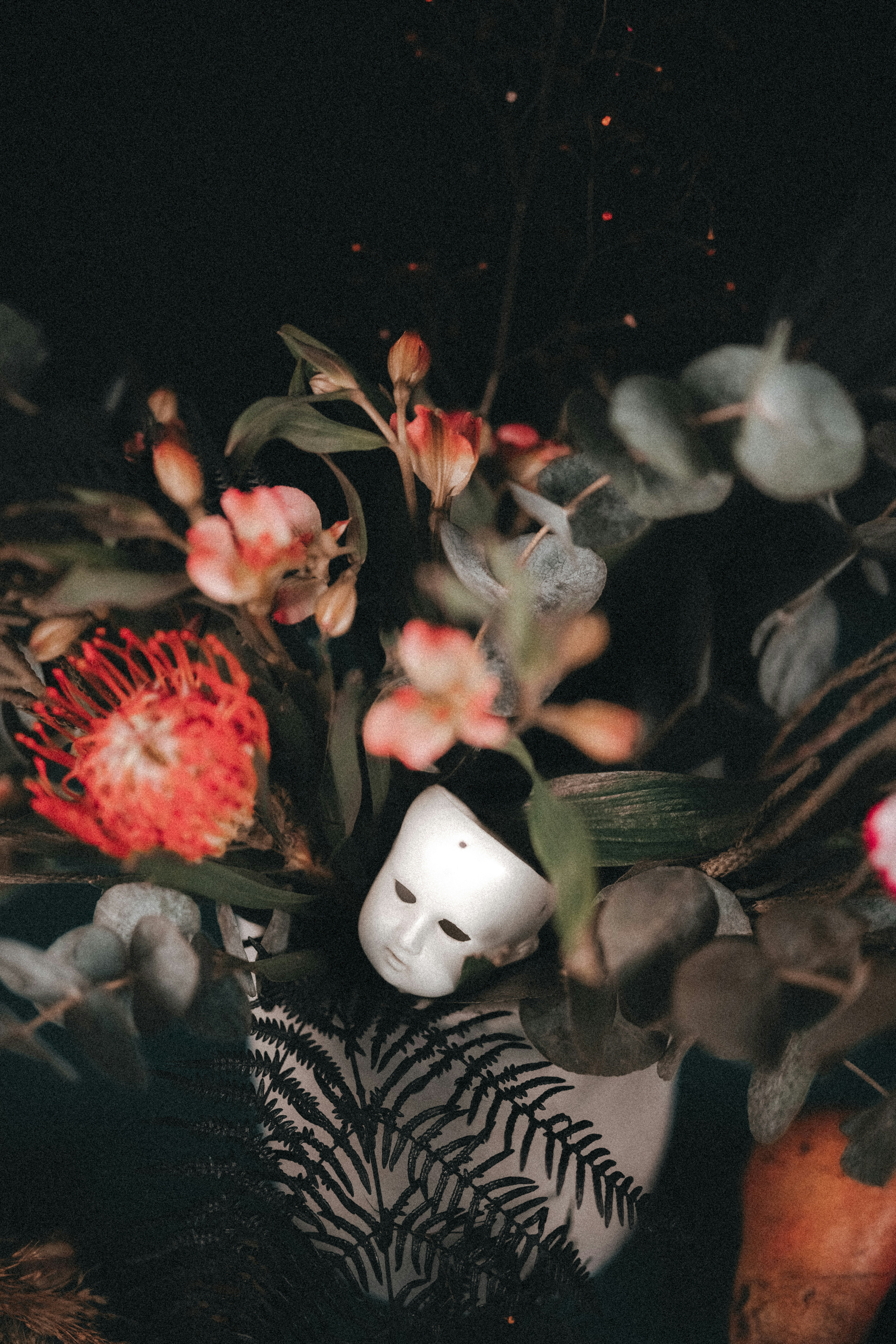 Masked Still Life: Red Florals and White Veiled Face Emerging from Shadows