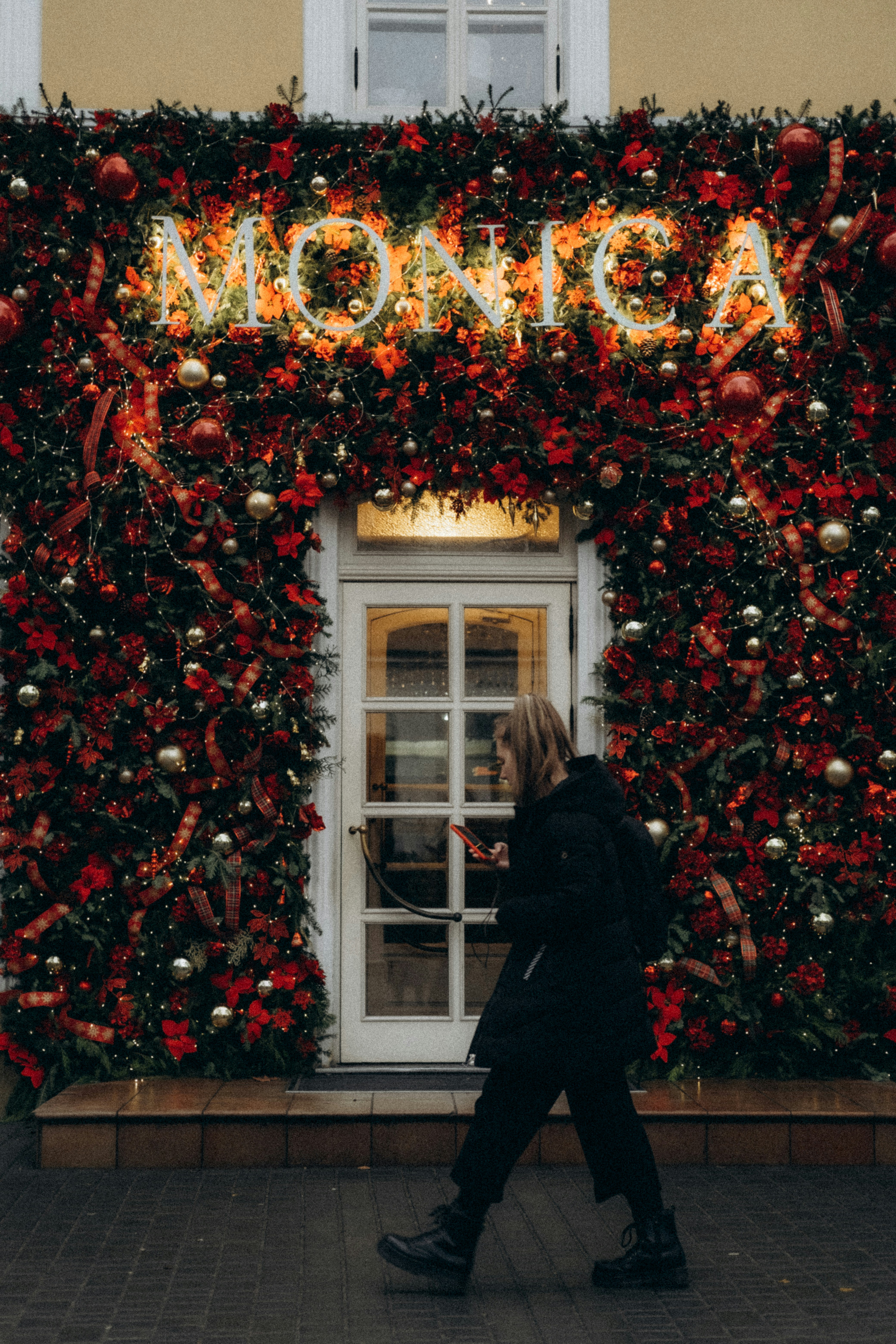 A Quiet Stride Under MONICA's Red-and-Gold Christmas Façade