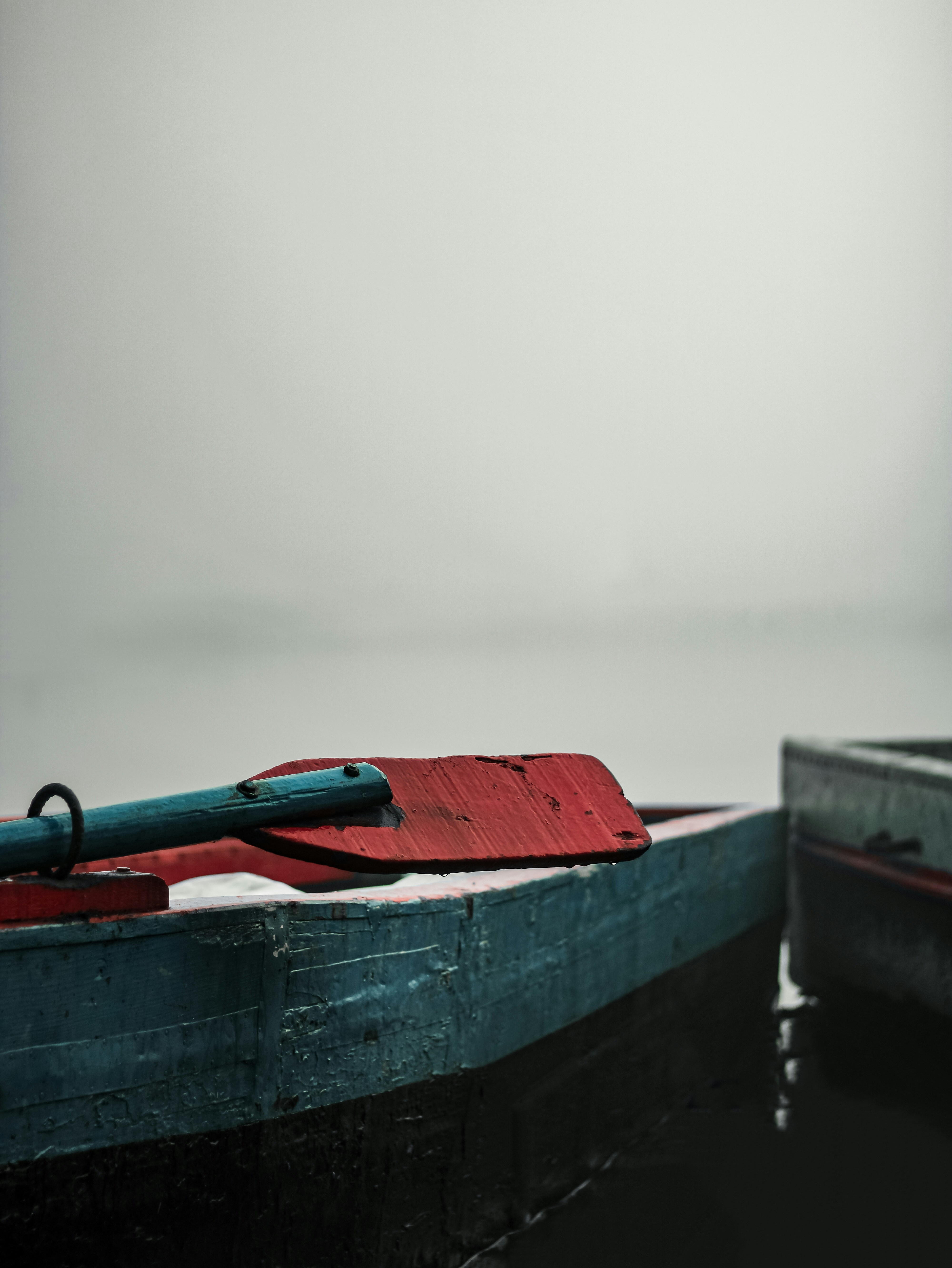 Red Oar Across a Weathered Blue Hull at the Quiet Harbor