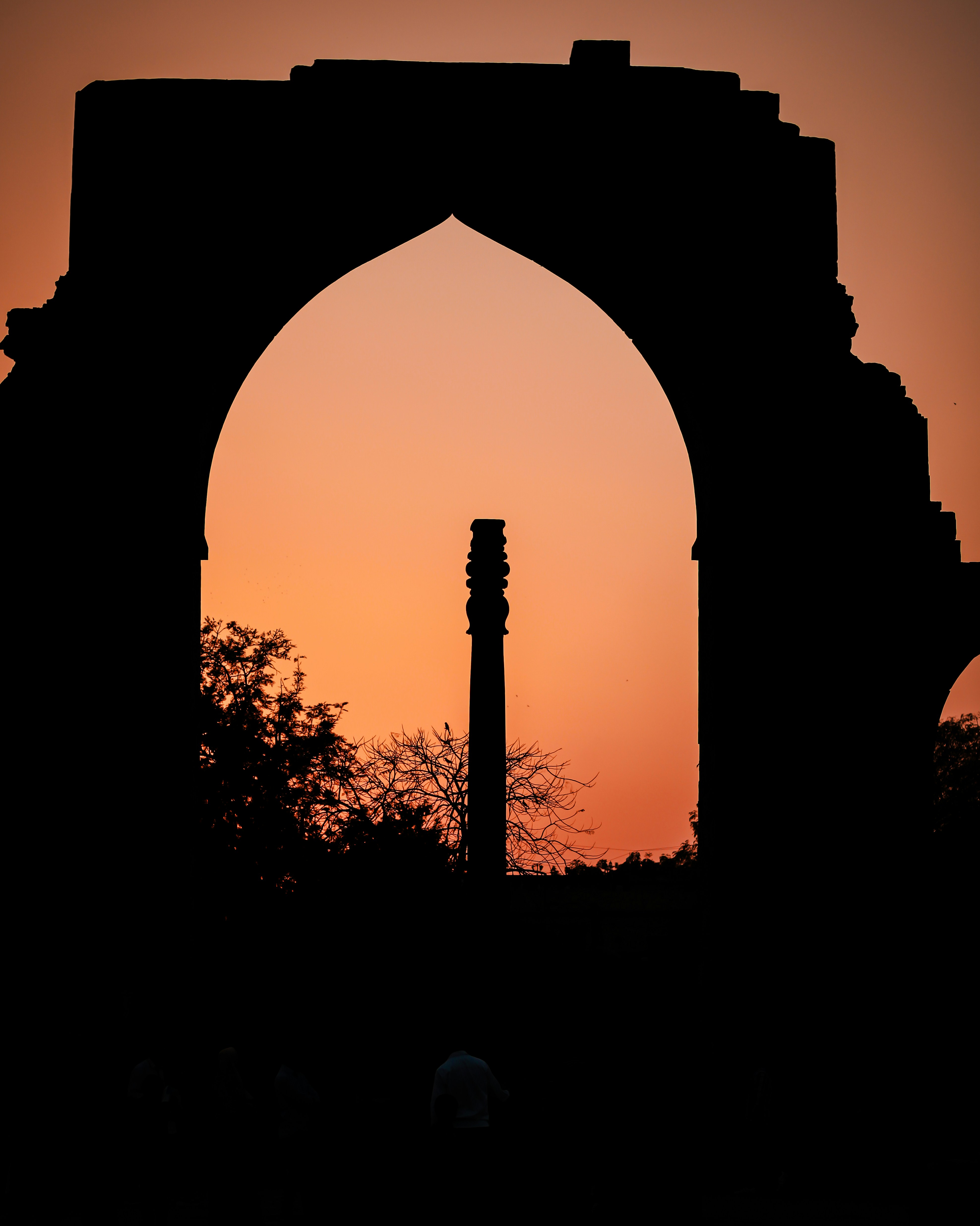 The sun is setting behind an arch in a building photo – Free ...