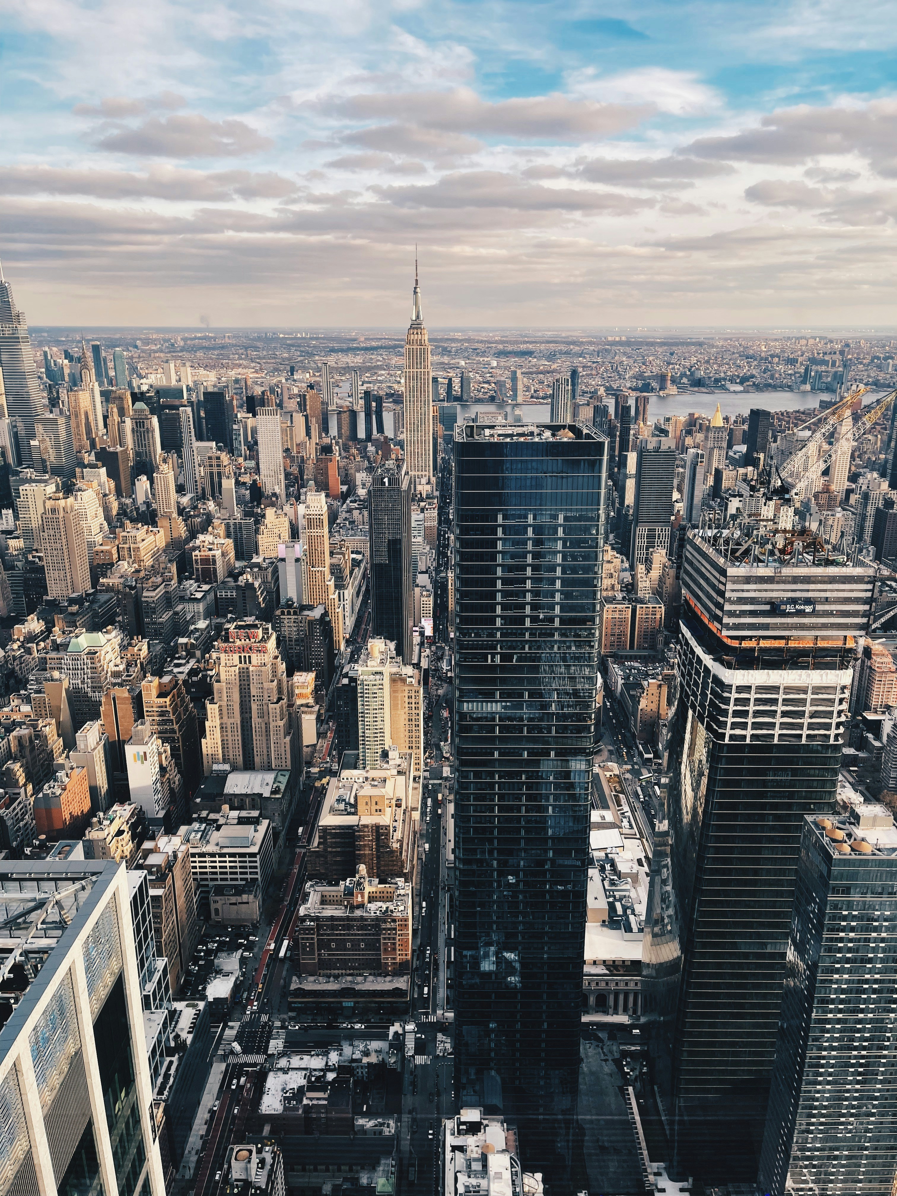 Aerial view of New York City showcasing a dynamic skyline with the Empire State Building prominently positioned among towering skyscrapers. The scene captures the essence of urban life.