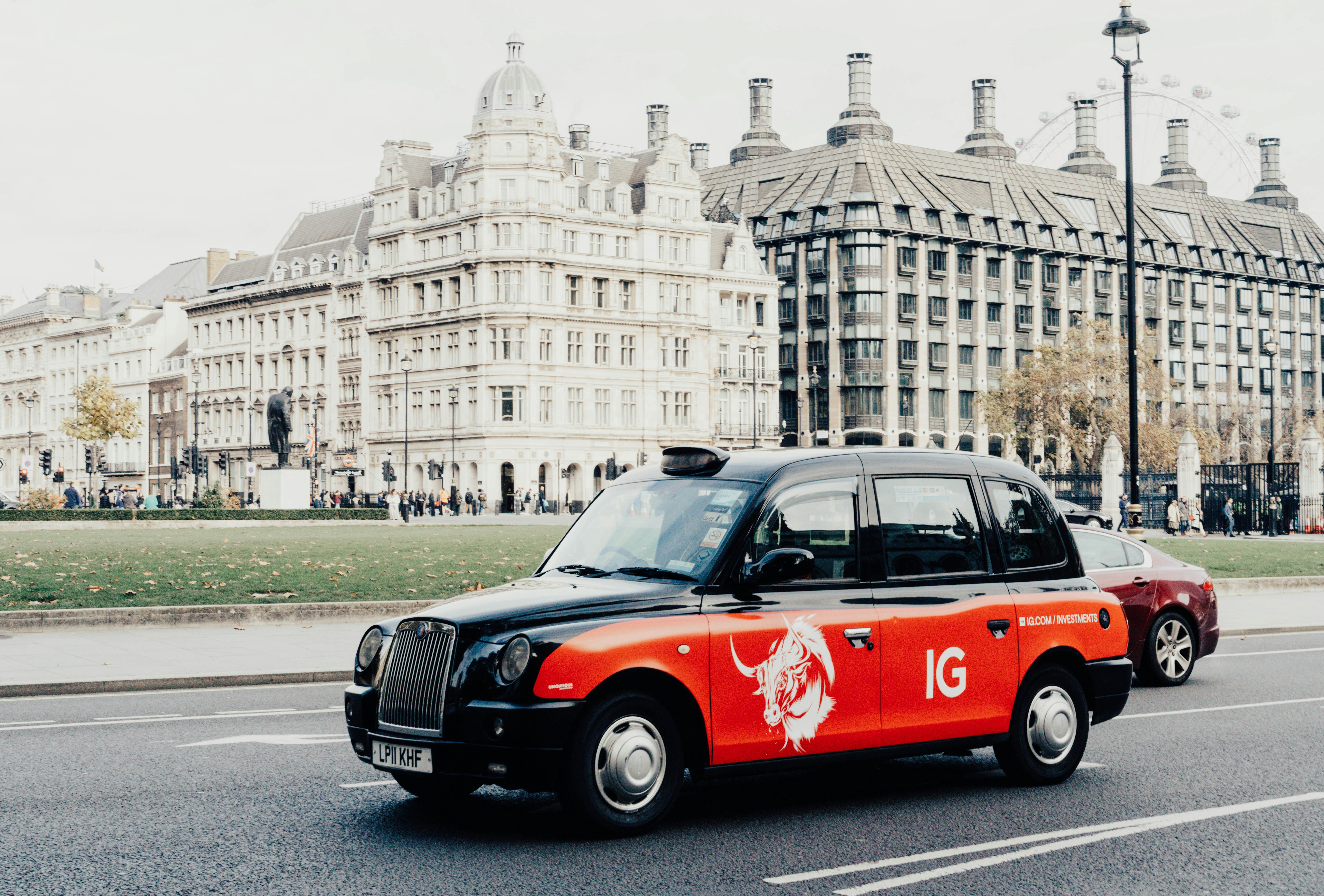 A red and black taxi cab driving down a street photo – Free London ...