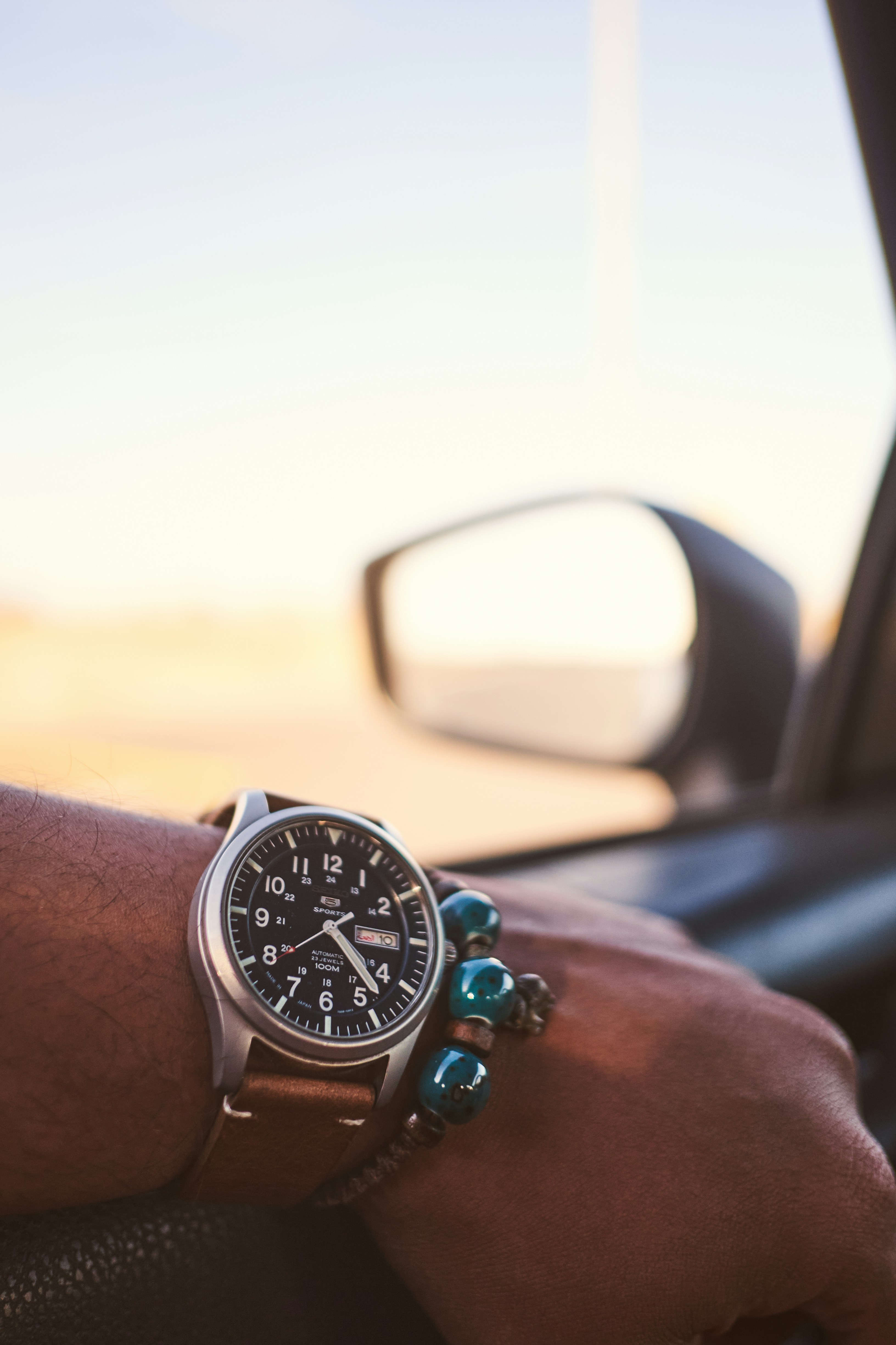 Timepiece on the Move: A Wristwatch and Turquoise Beads in a Car Cabin