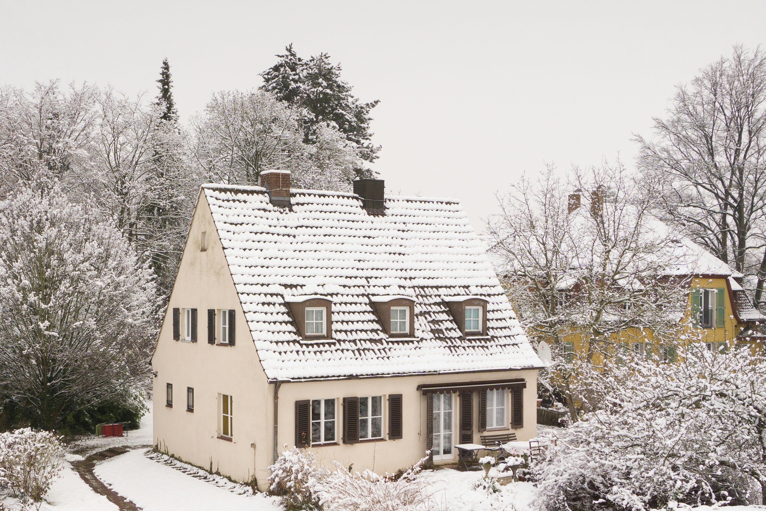 Charming house blanketed in fresh snow, surrounded by frosty trees and a tranquil landscape.