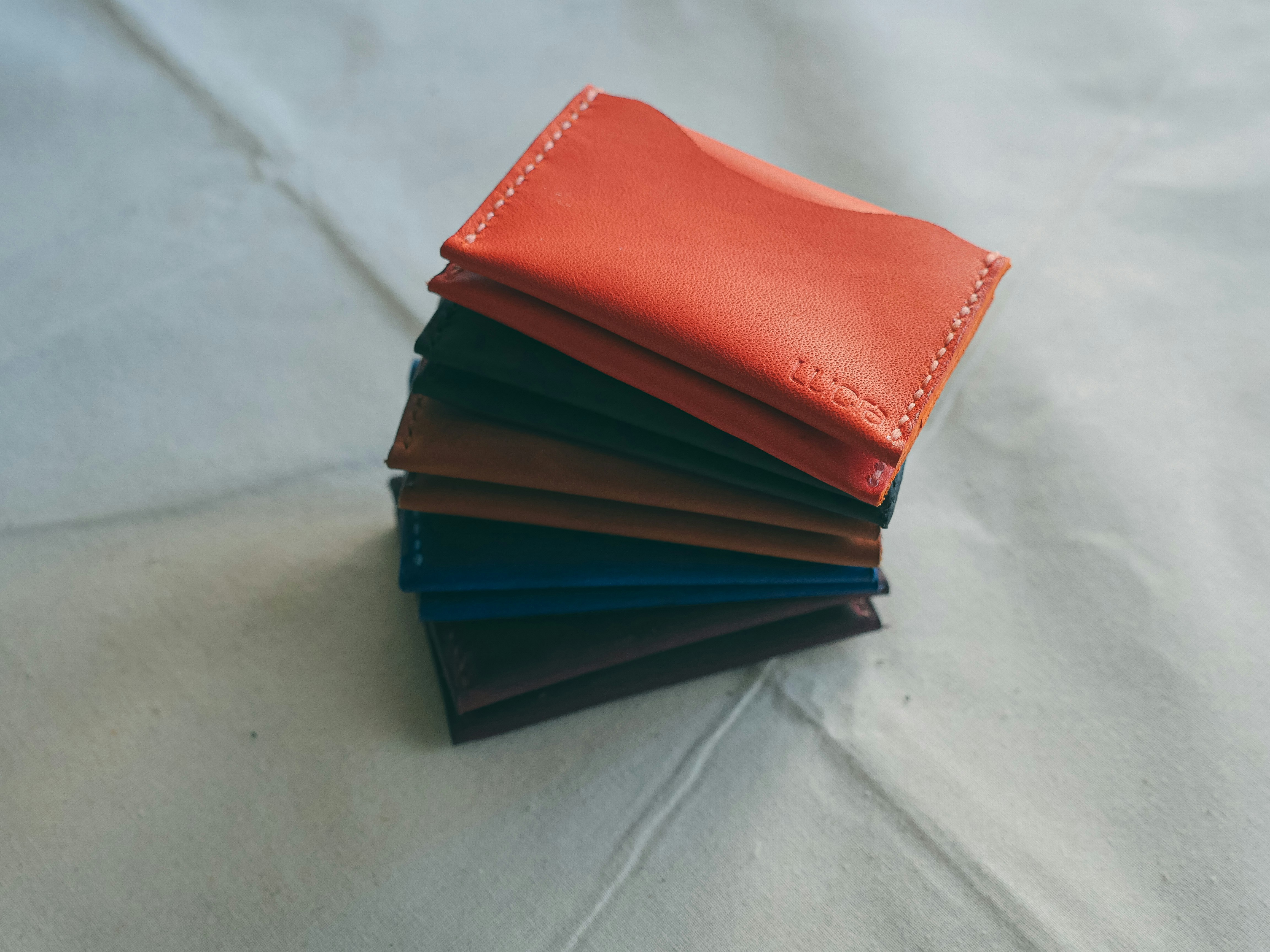 A stack of four different colored wallets sitting on top of each other ...